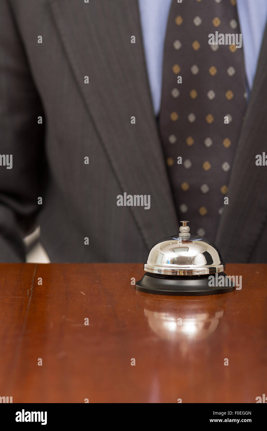hotel bell in reception desk with man wearing suit in the background ...
