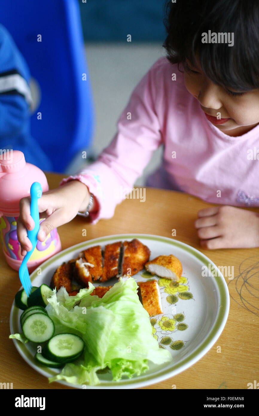 Children eating chicken meat and salad Stock Photo - Alamy
