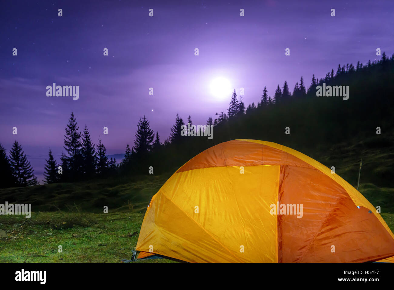 Illuminated orange camping tent under moon, stars at night Stock Photo ...