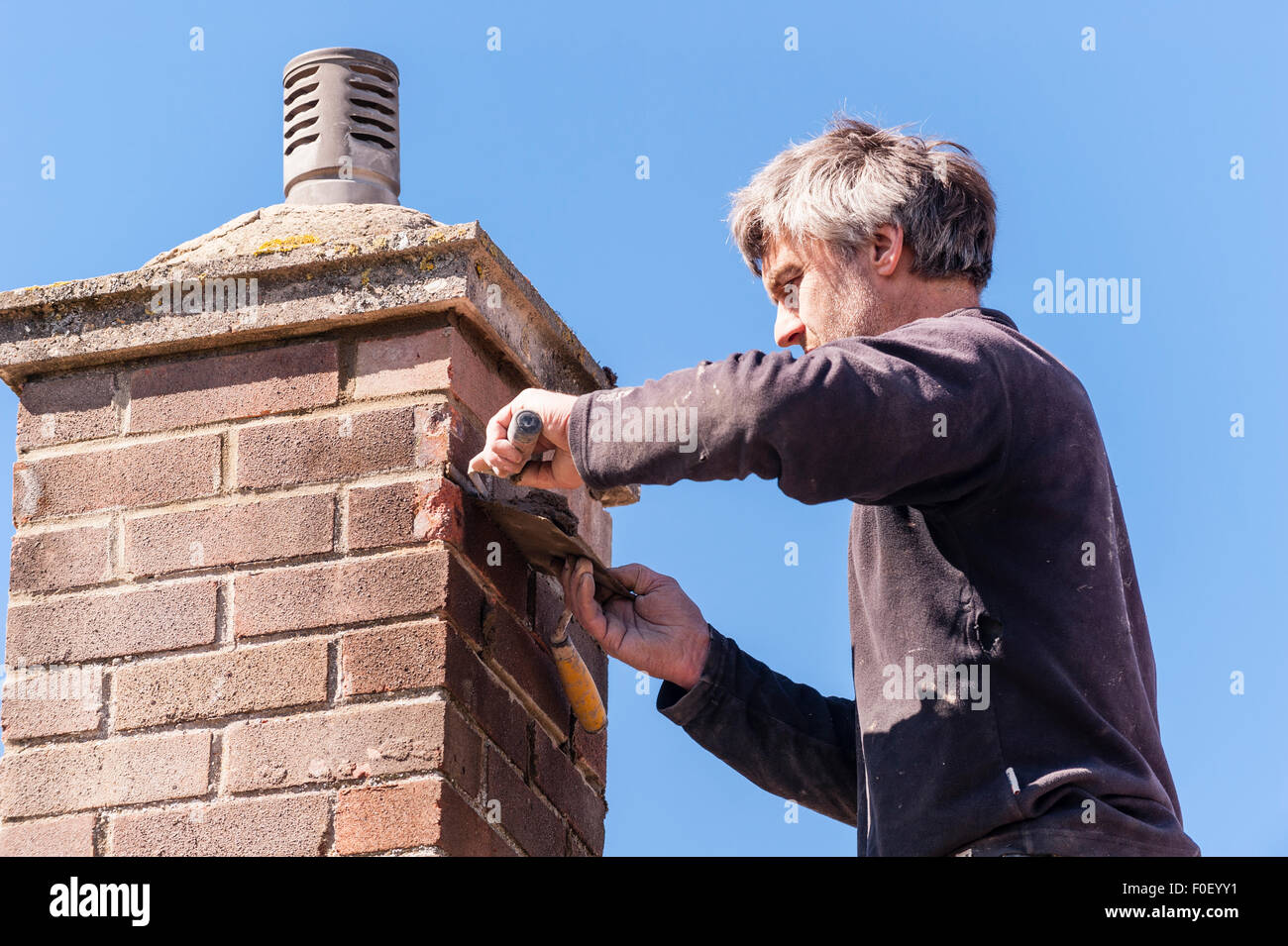 A Builder in the process of repointing a chimney in the UK Stock Photo ...
