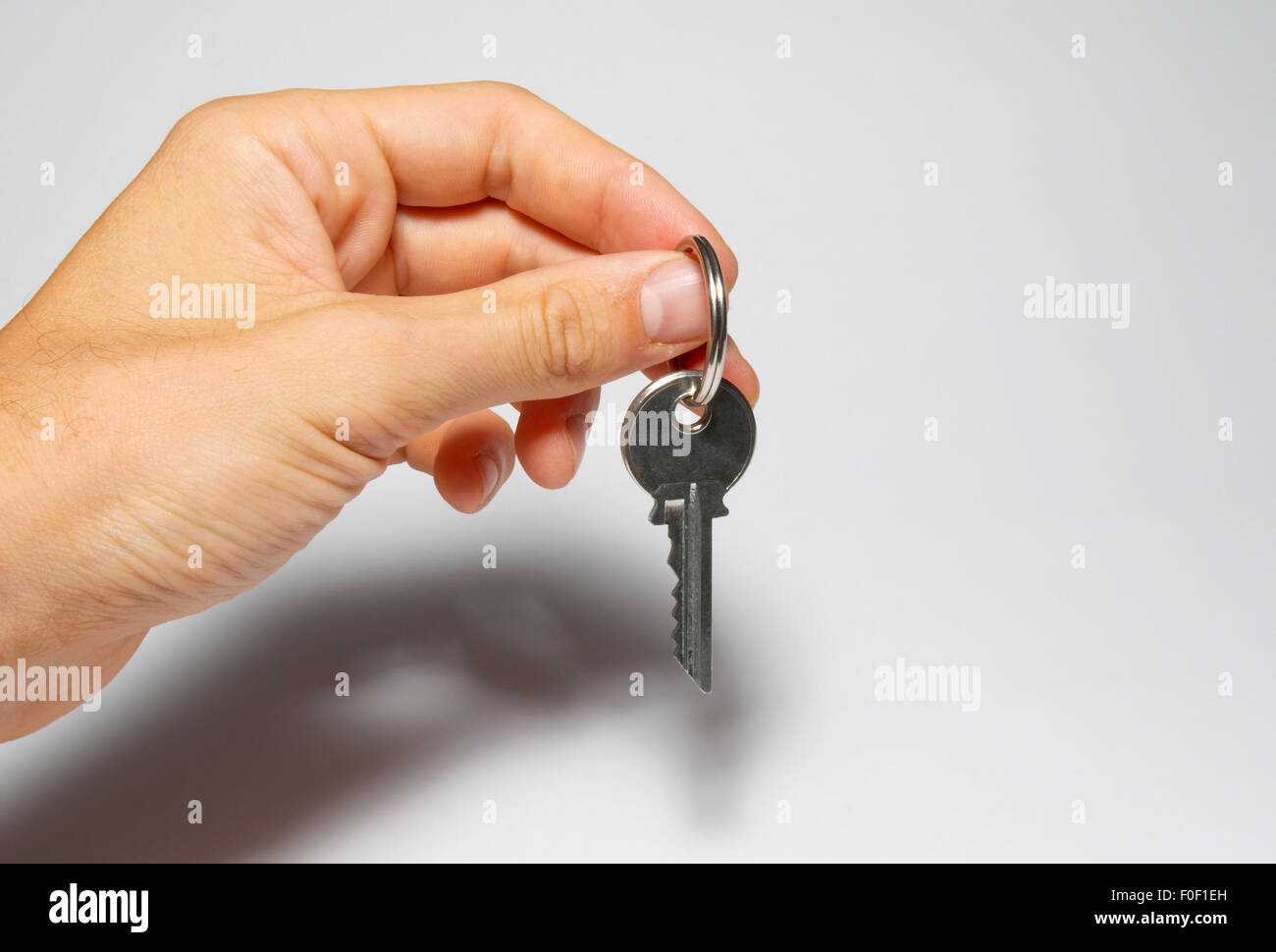 Silver key in a hand on gray background Stock Photo - Alamy
