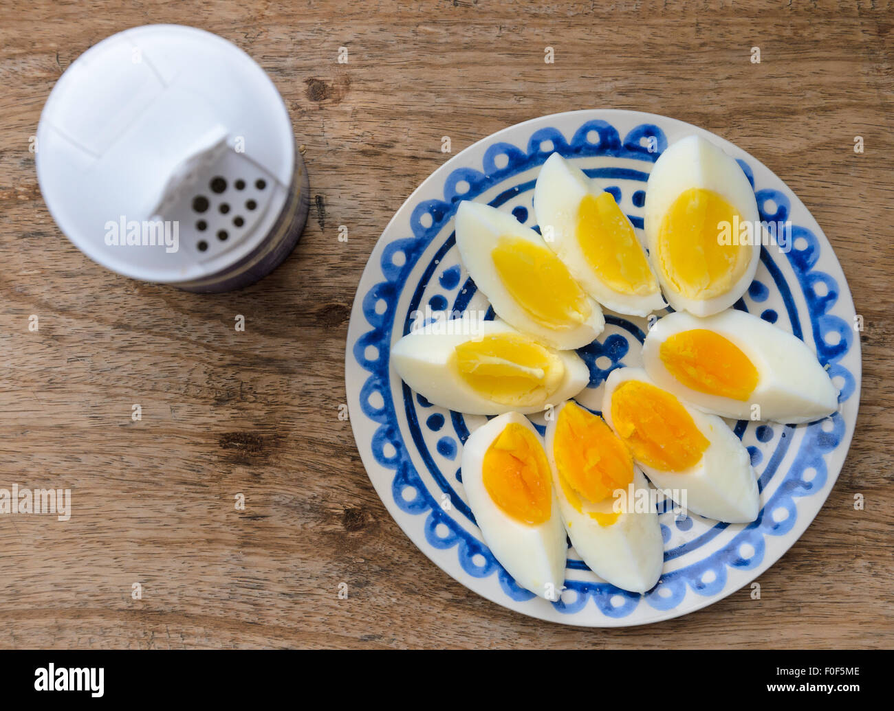 Two colors yolk, sliced hard boiled eggs in a blue decorated plate on wooden kitchen table Stock ...