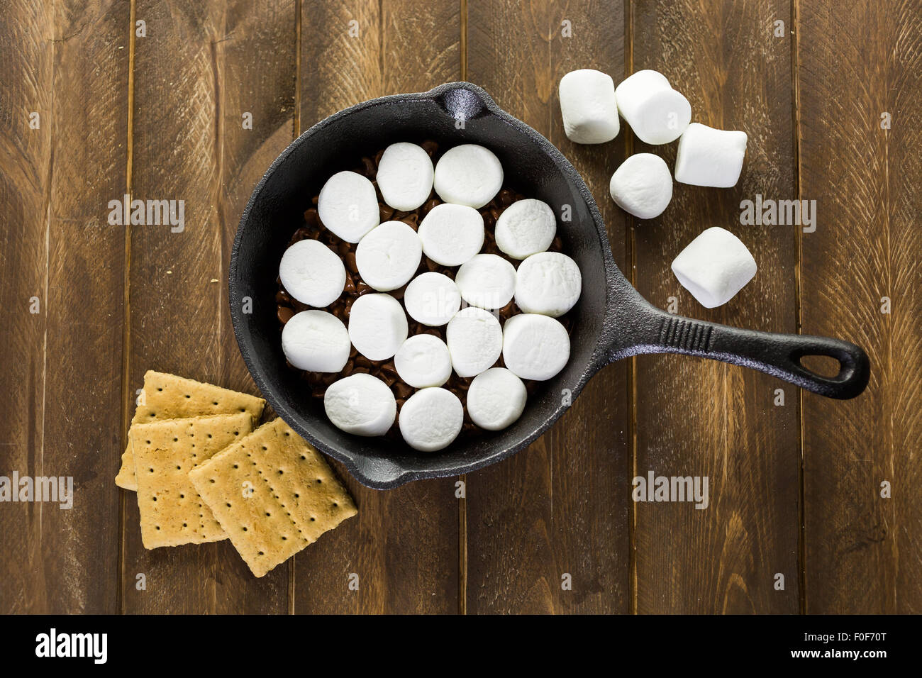 Preparing smores dip prepared with large marshmallows in cast iron pan ...