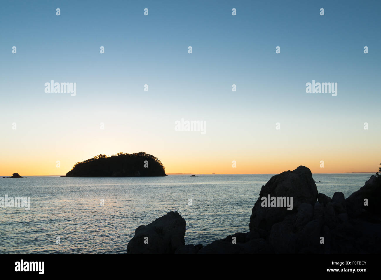 Stunning sky at sunrise silhouette rocky coast and off-shore island ...