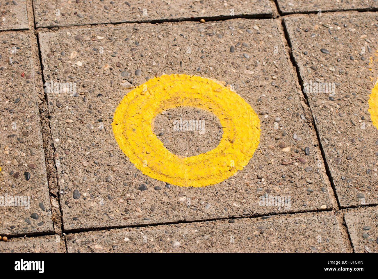 number zero painted bright yellow paint on a gray tile of pathway ...