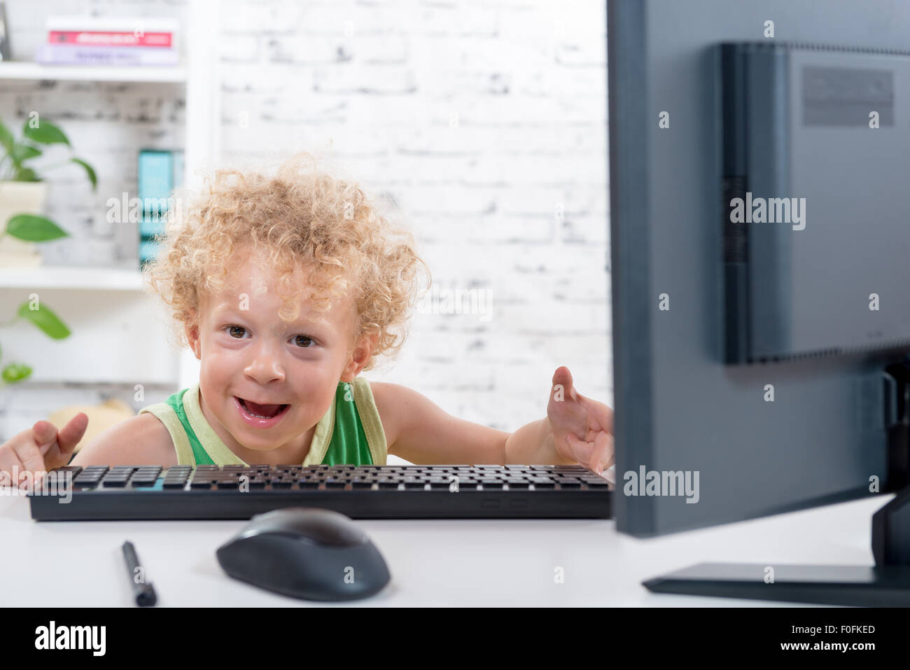 a little blond boy playing with the keyboard of a computer Stock Photo ...
