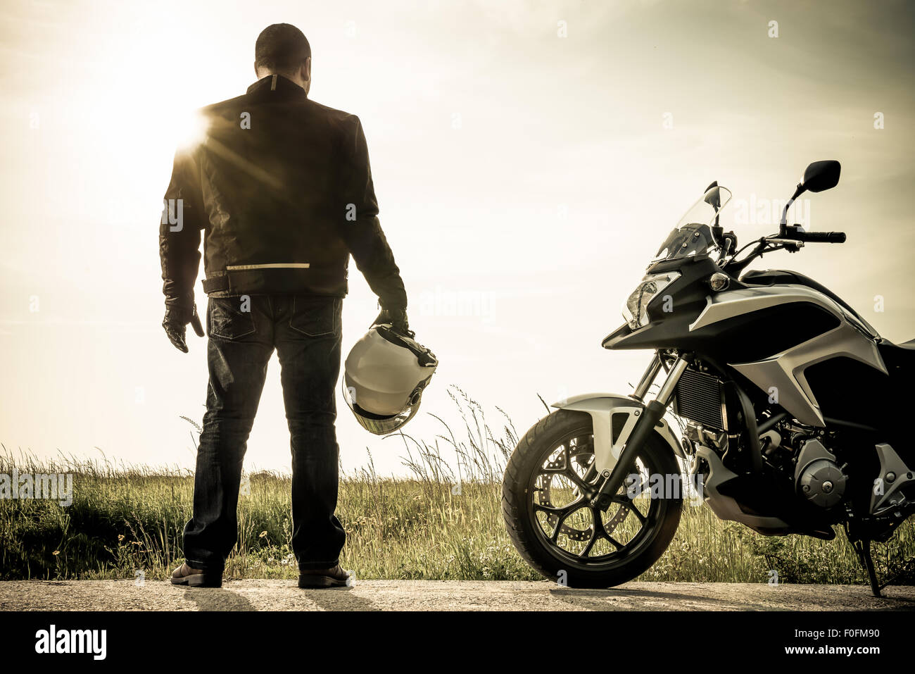 Biker standing with its motorbike on a misty sunset Stock Photo - Alamy