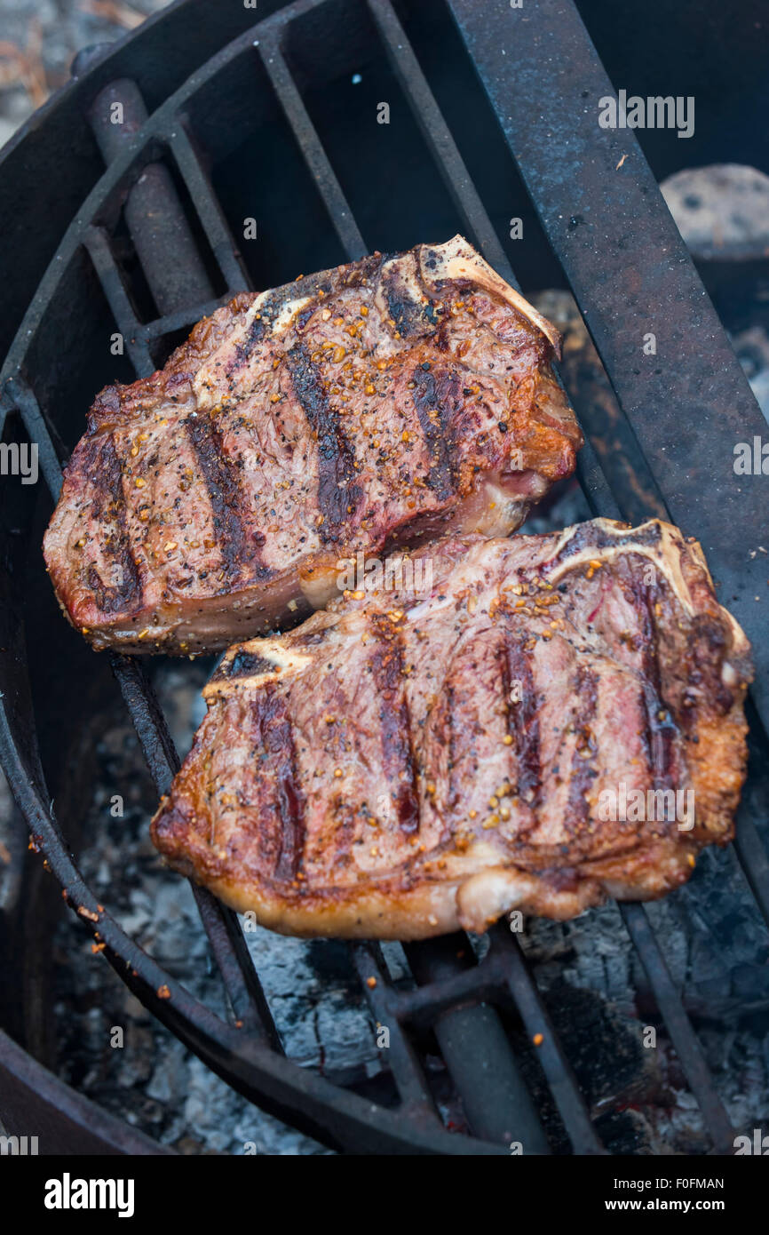 Pair of steaks grilling over a campfire Stock Photo - Alamy