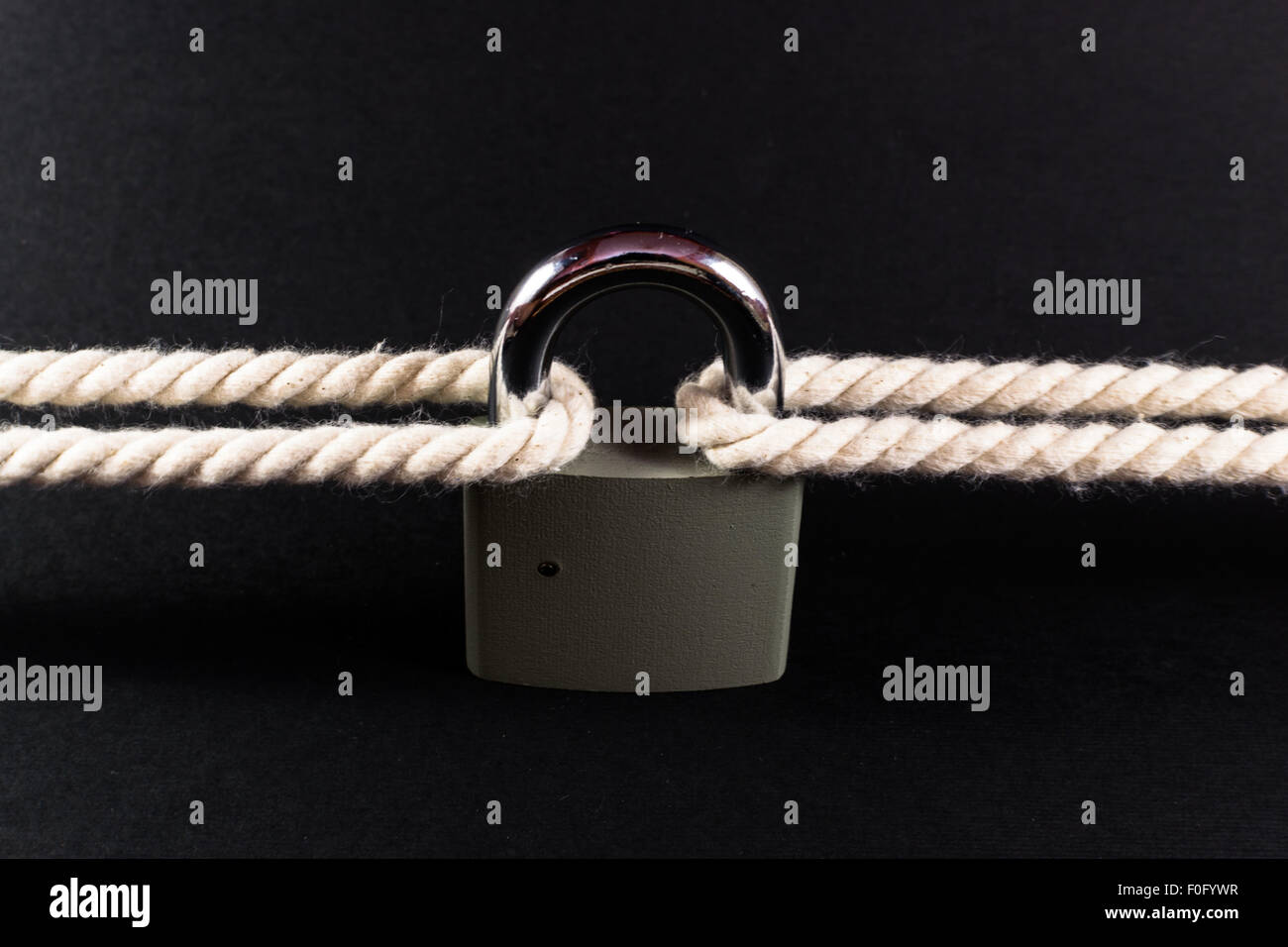 Locked padlock secures two separate ropes together Stock Photo - Alamy
