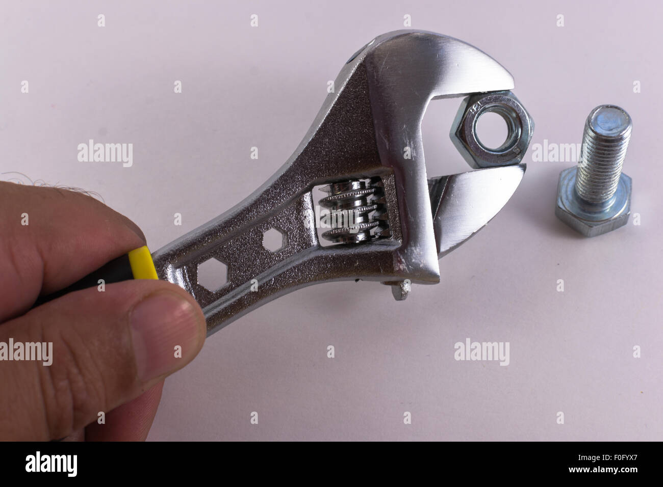 Human hand holding an adjustable spanner and fixing a nut to a bolt on ...