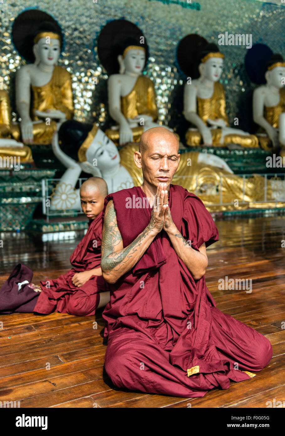 Buddhist monk praying with young Buddhist monk in the background ...