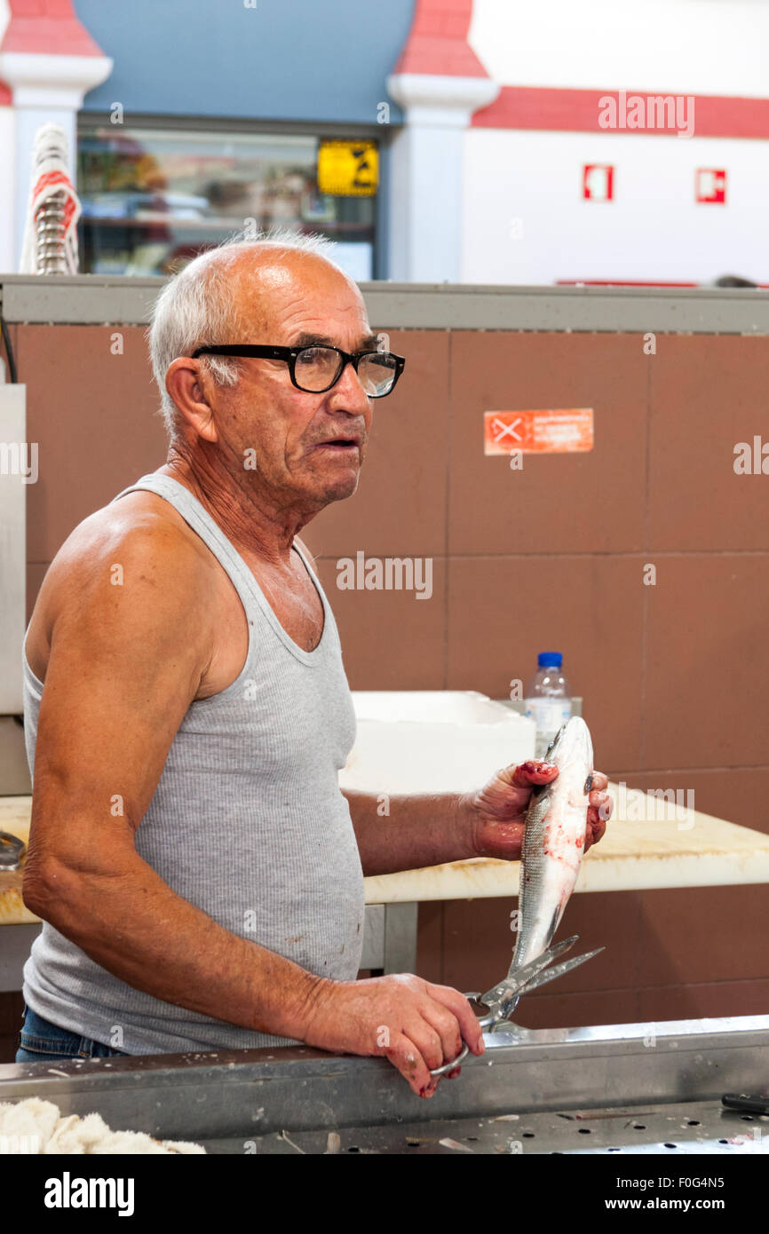 Fish seller preparing a fish in the traditional market hall in Loule ...