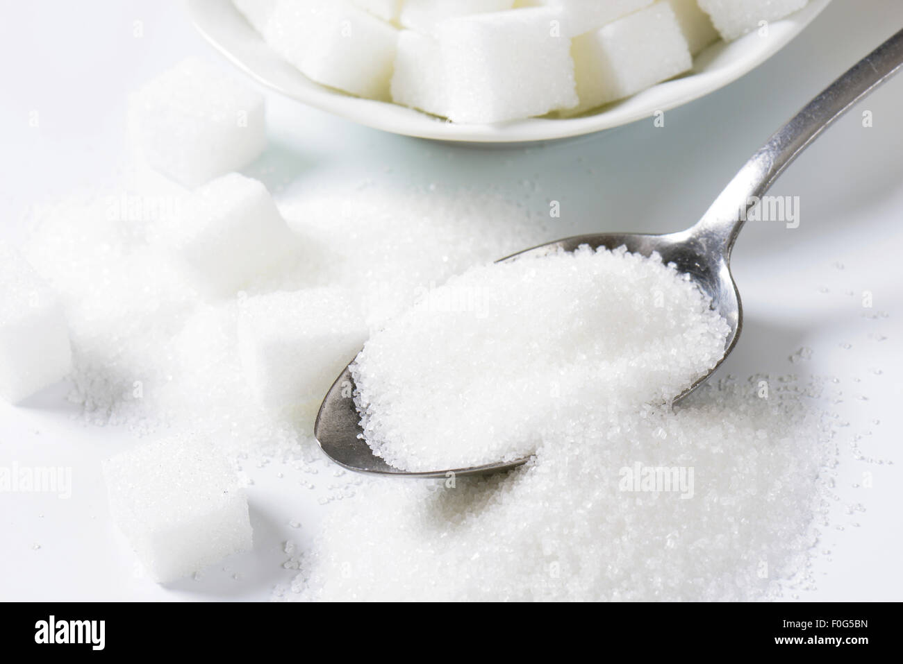 Spoonful of fine granulated sugar and pile of sugar cubes Stock Photo ...