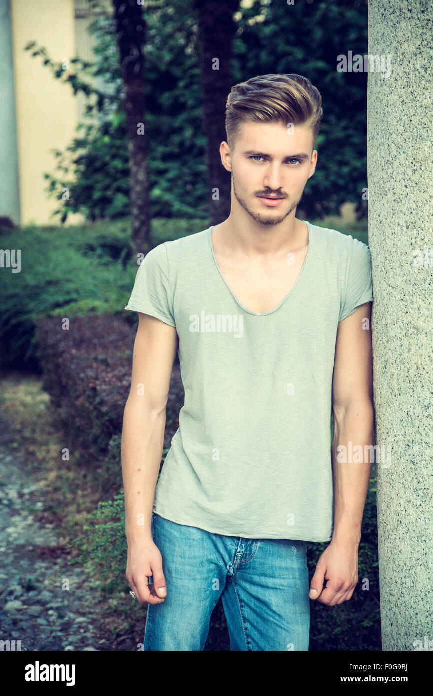 Handsome young man standing outdoors under old colonnade in european ...