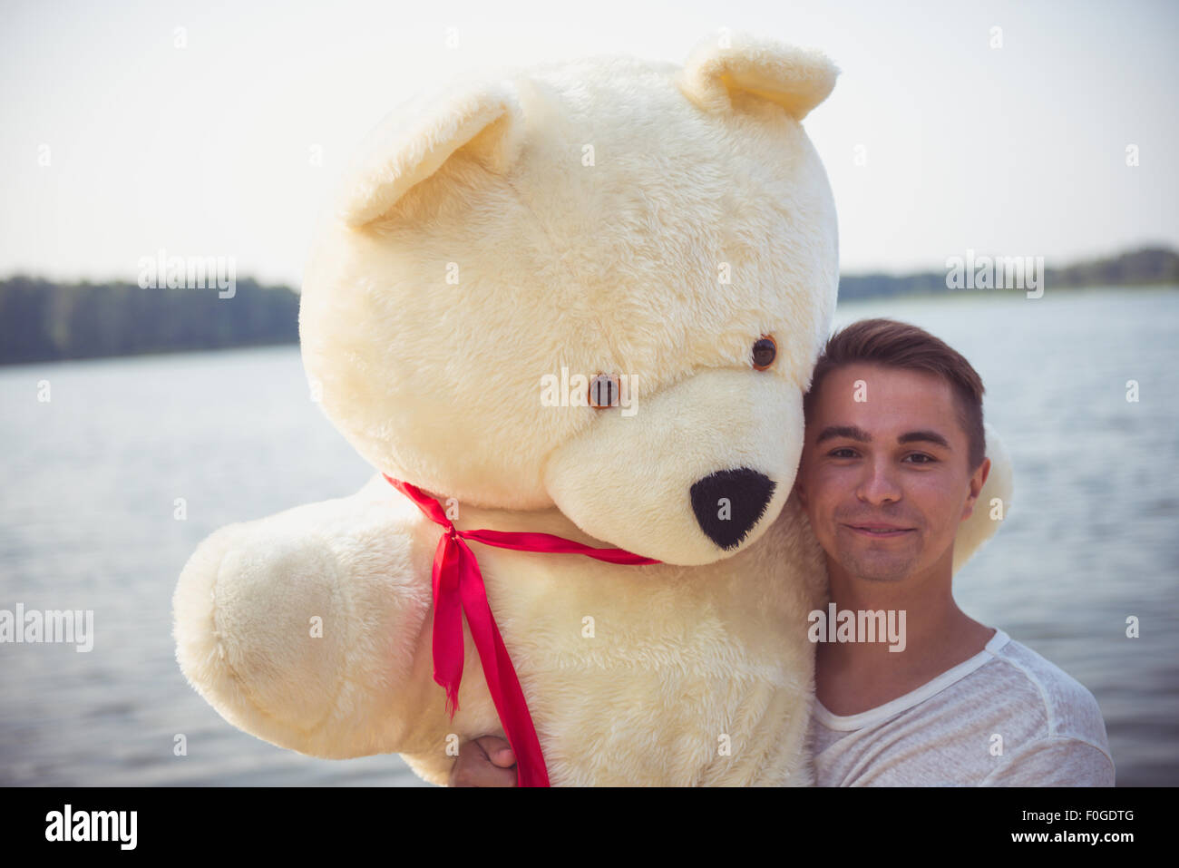 Handsome young man is fooling around with his massive teddy bear Stock ...