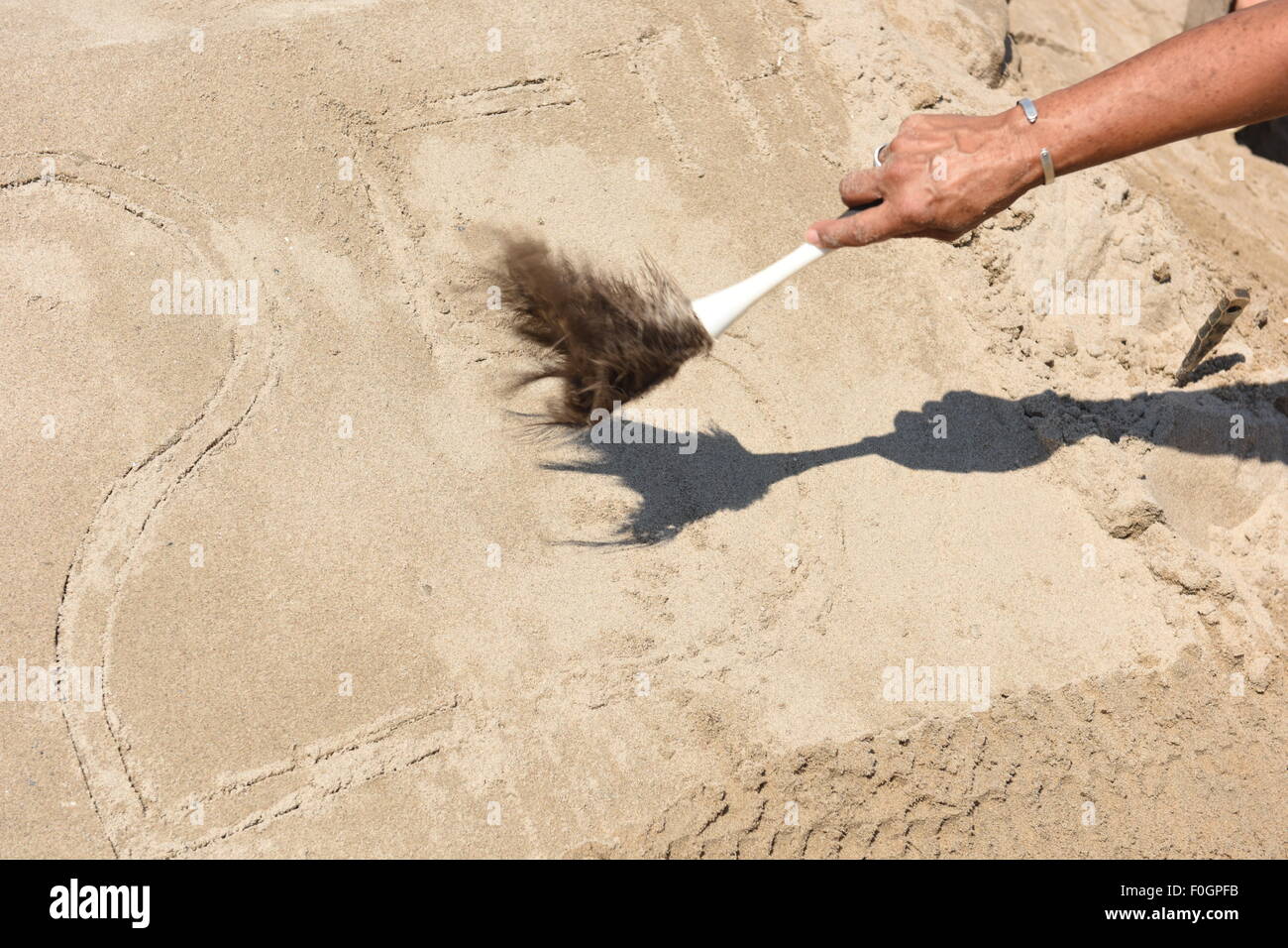 Brooklyn, United States. 15th Aug, 2015. Brushing sand with feather ...