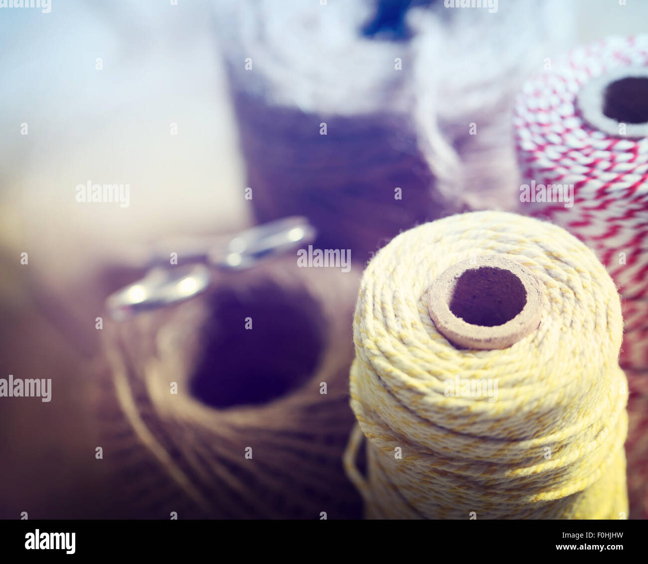 Spools of different color string with scissors Stock Photo - Alamy