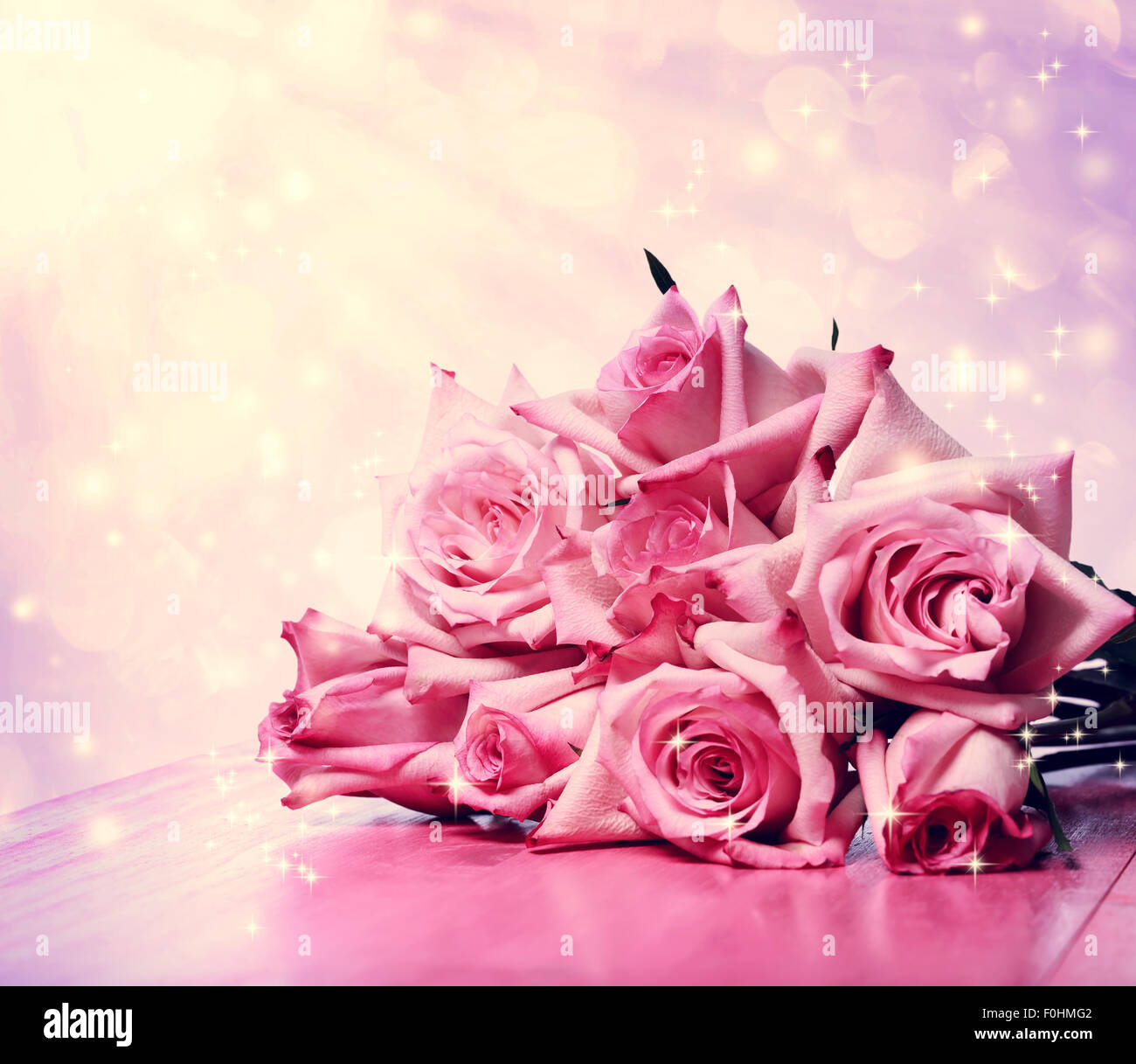 Beautiful pink roses on pink wooden table over shiny background Stock ...