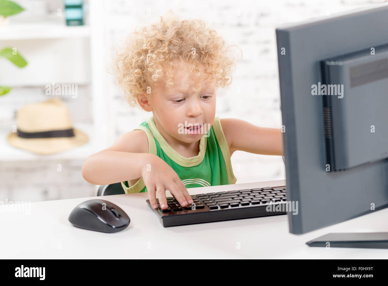 a little blond boy playing with the keyboard of a computer Stock Photo ...