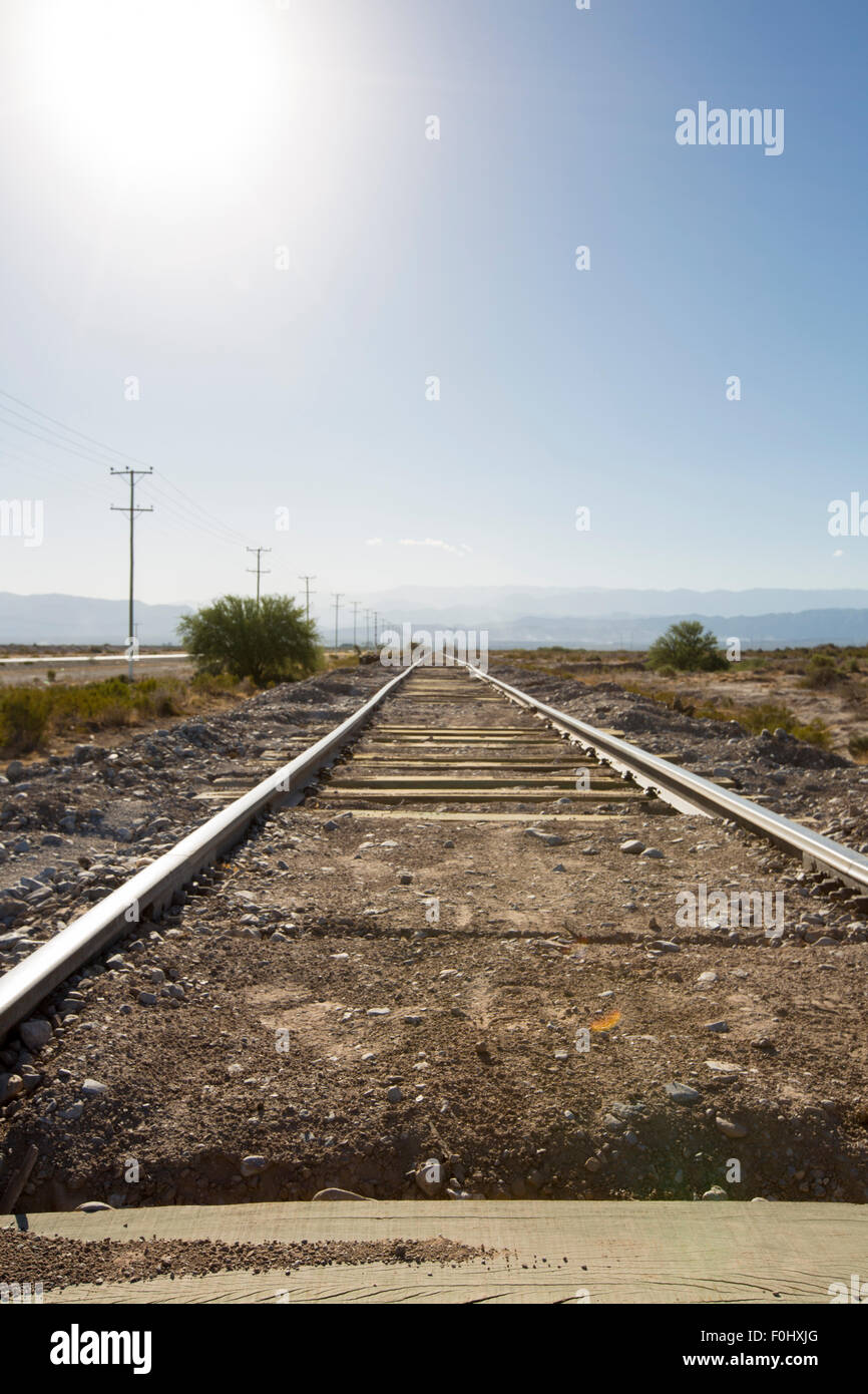 Landscape of a straight train rail way going towards the mountains ...