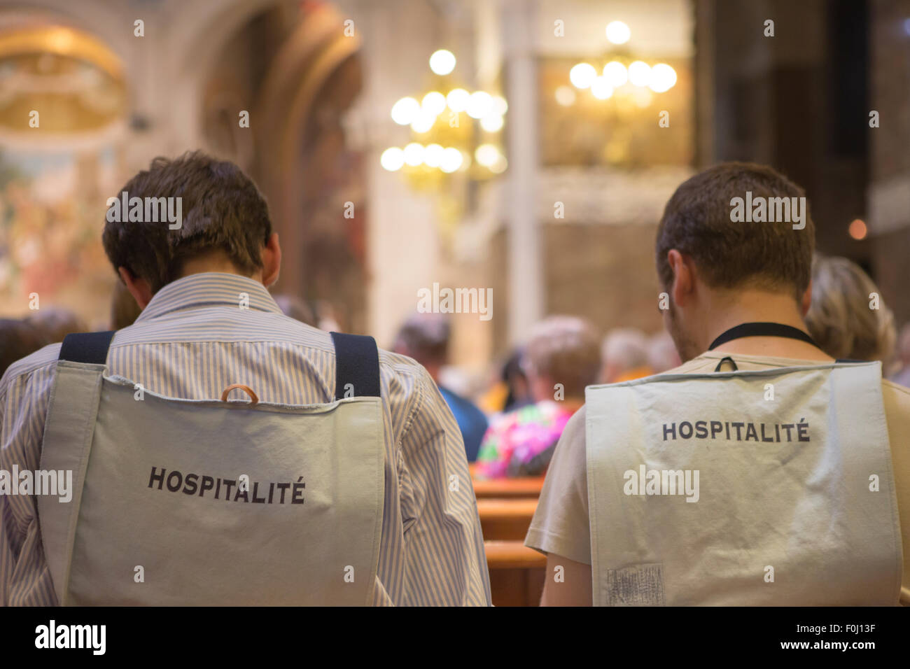 Back of volunteers in Lourdes in the church. Volunteer helpers in ...