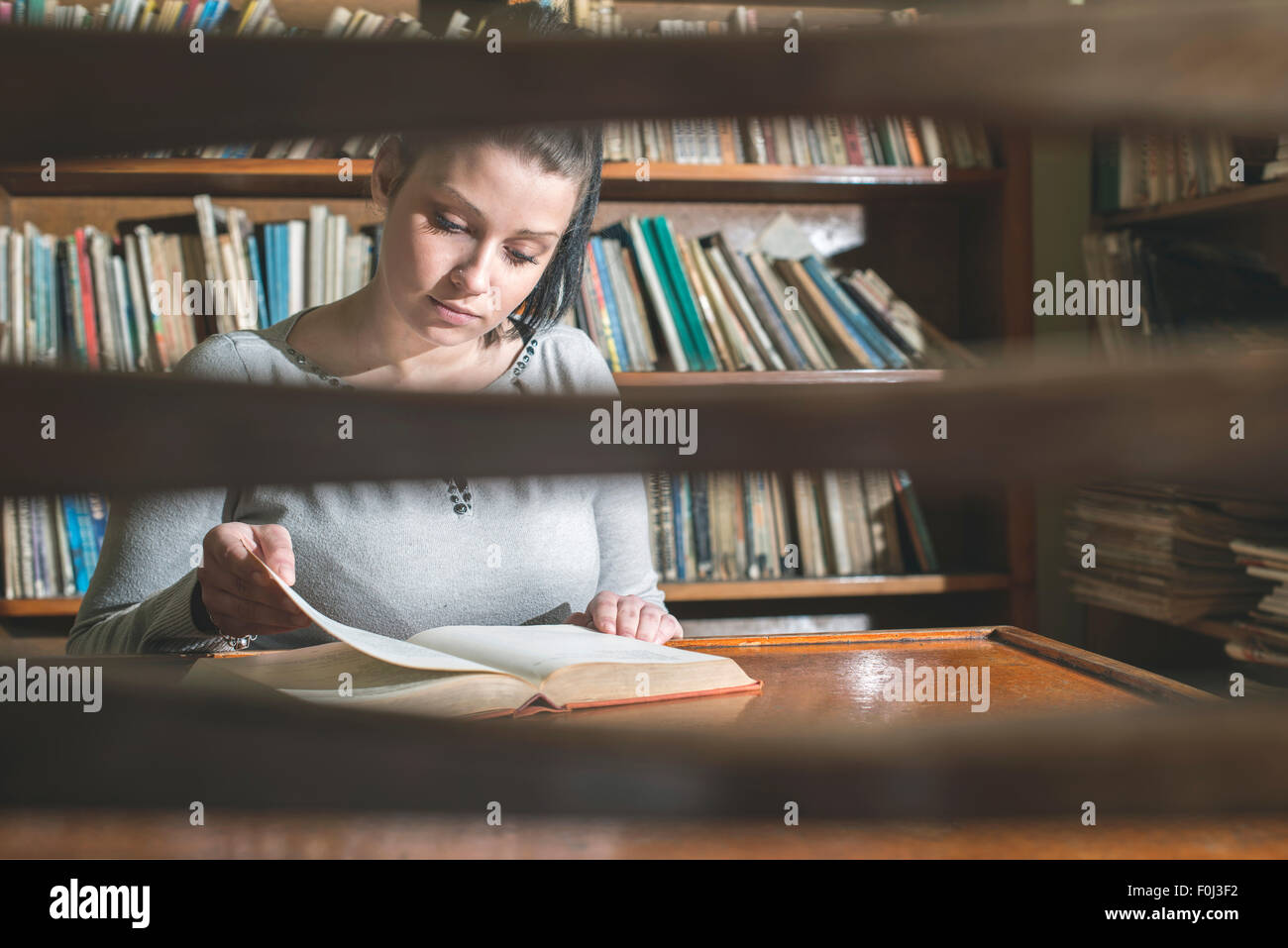 Student girl in a library. Looking at book Stock Photo - Alamy