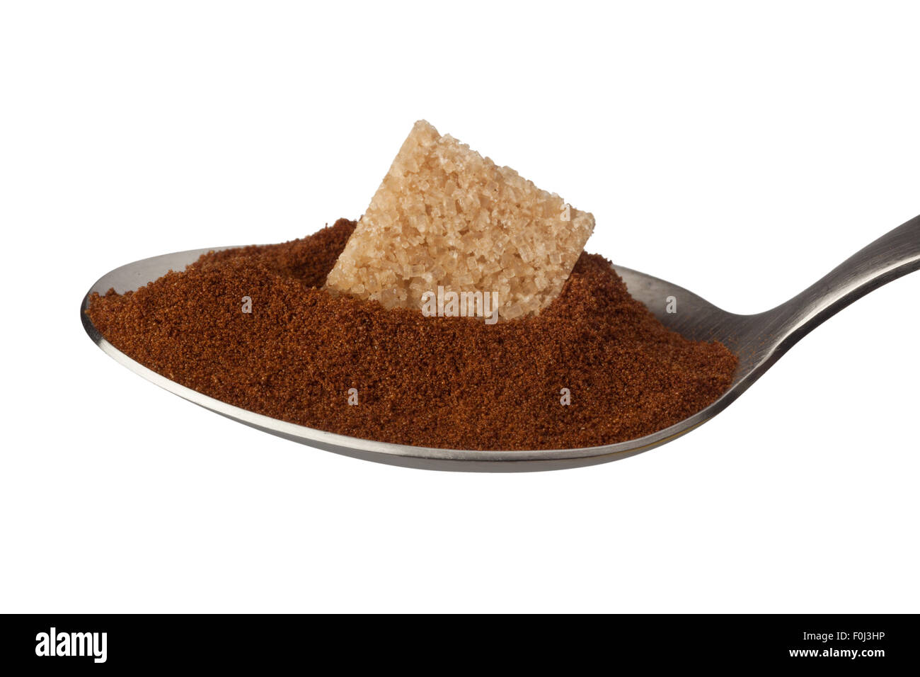 Instant coffee powder and brown sugar cube on a spoon isolated on white ...