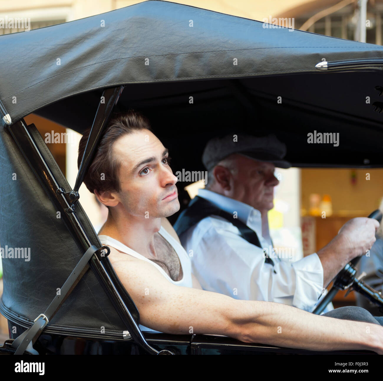 Young man and an older gentleman driving an old early 1900's car ...
