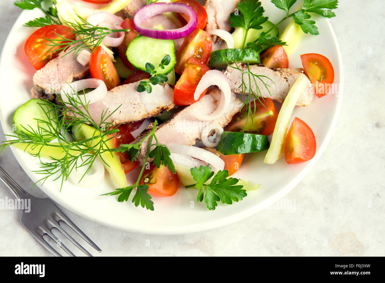 Colorful vegetable salad with meat (roasted pork) on white plate and ...
