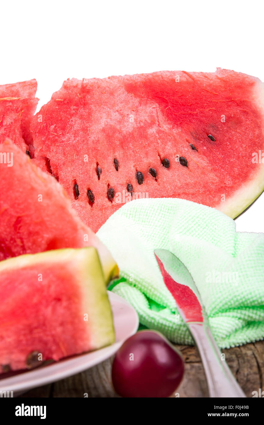 slices of watermelon on the plate next with plums on a wooden ...