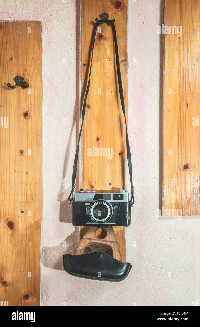 Vintage photo camera hooked on the hanger on the wall Stock Photo - Alamy