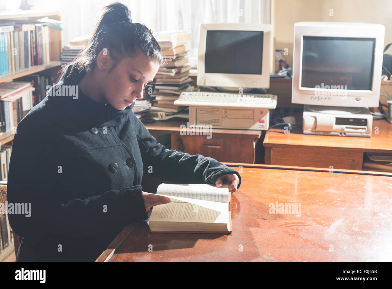 Student girl in a library. Looking at book Stock Photo - Alamy