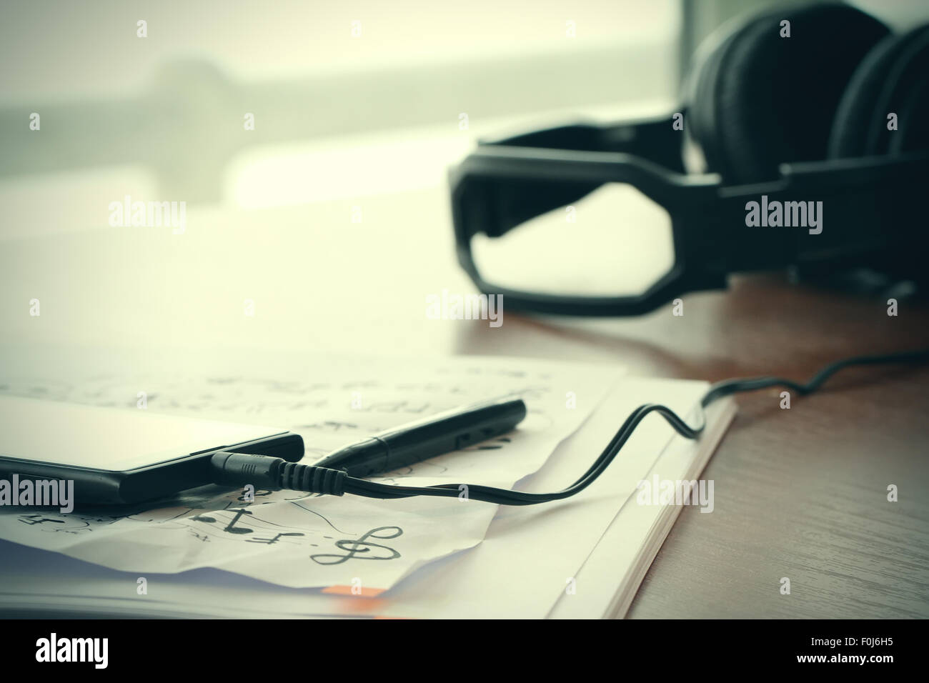 Closeup jack of smart phone with headphone on musical notes paper with ...