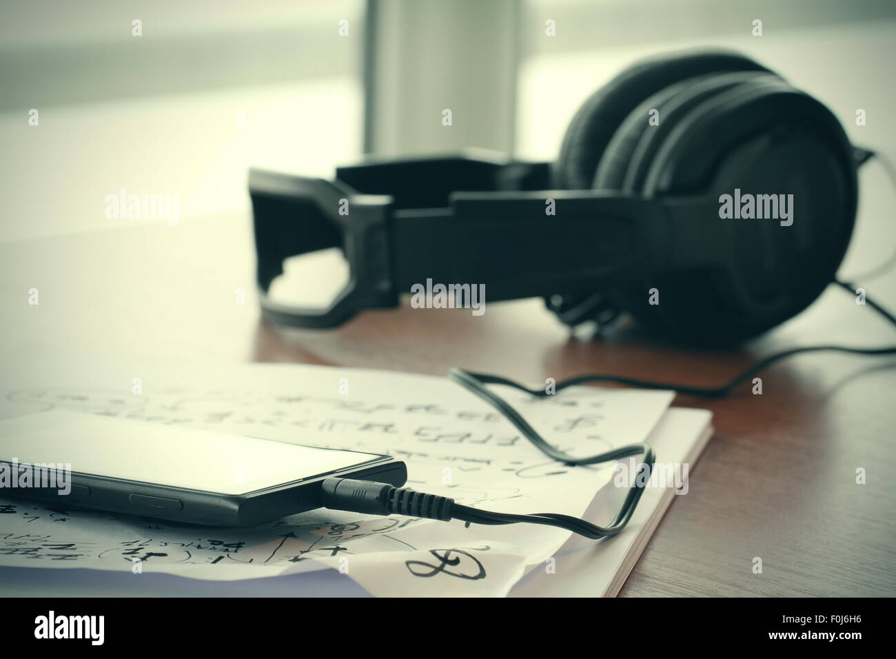 Closeup jack of smart phone with headphone on musical notes paper with ...