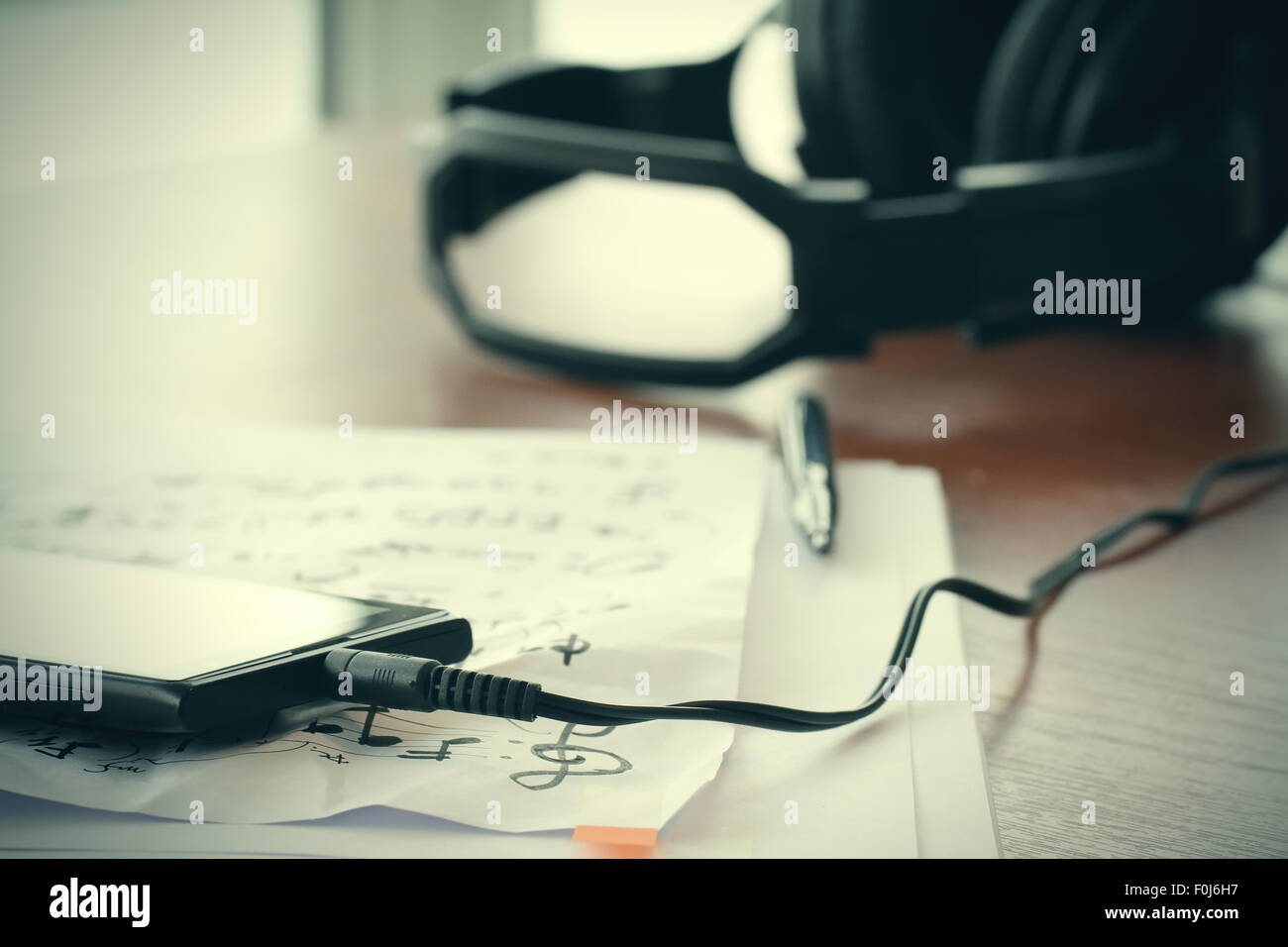 Closeup jack of smart phone with headphone on musical notes paper with ...