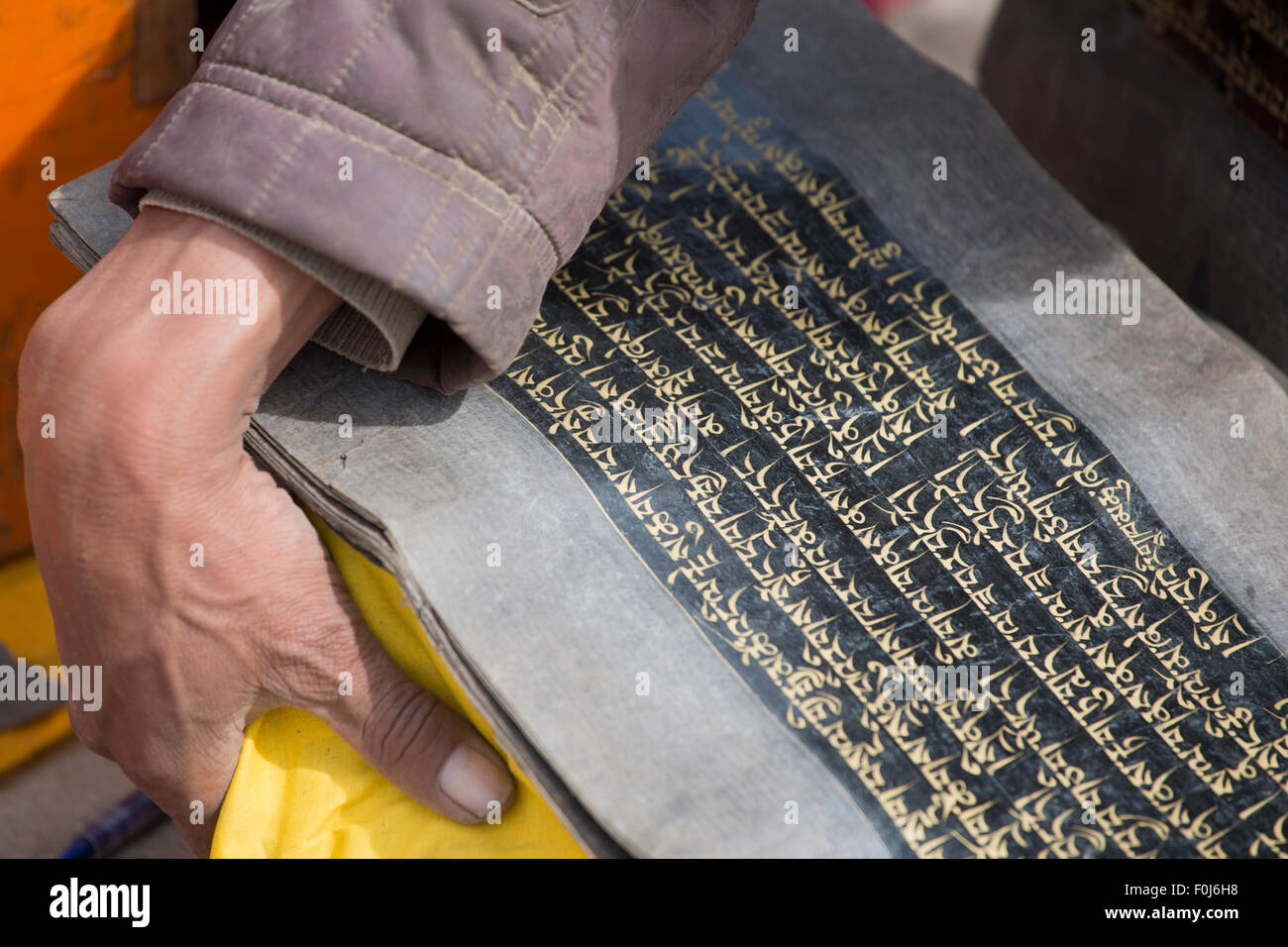 Close-up of a hand carrying a few old and holy Tibetan scripts. The ...