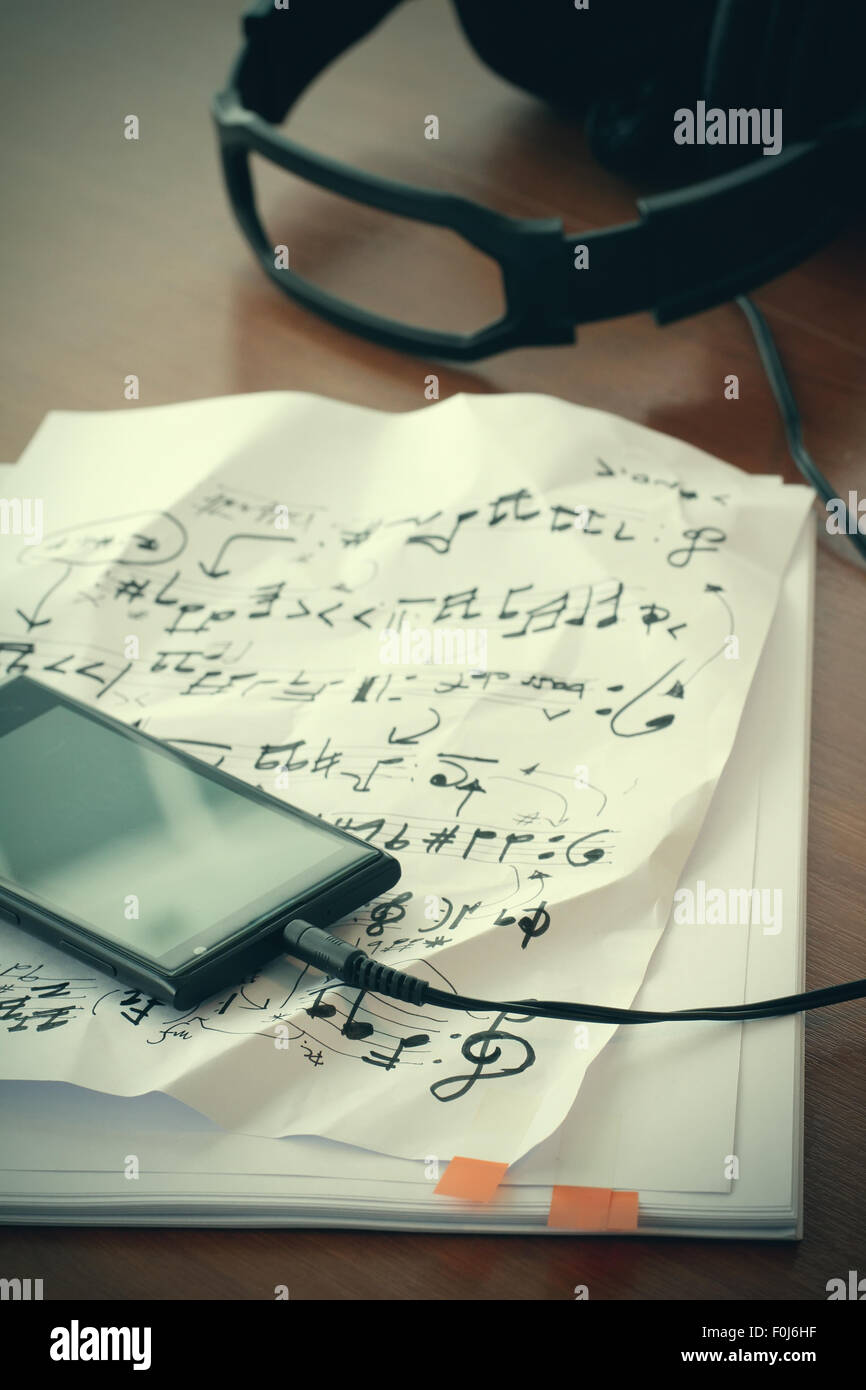 Closeup jack of smart phone with headphone on musical notes paper with ...