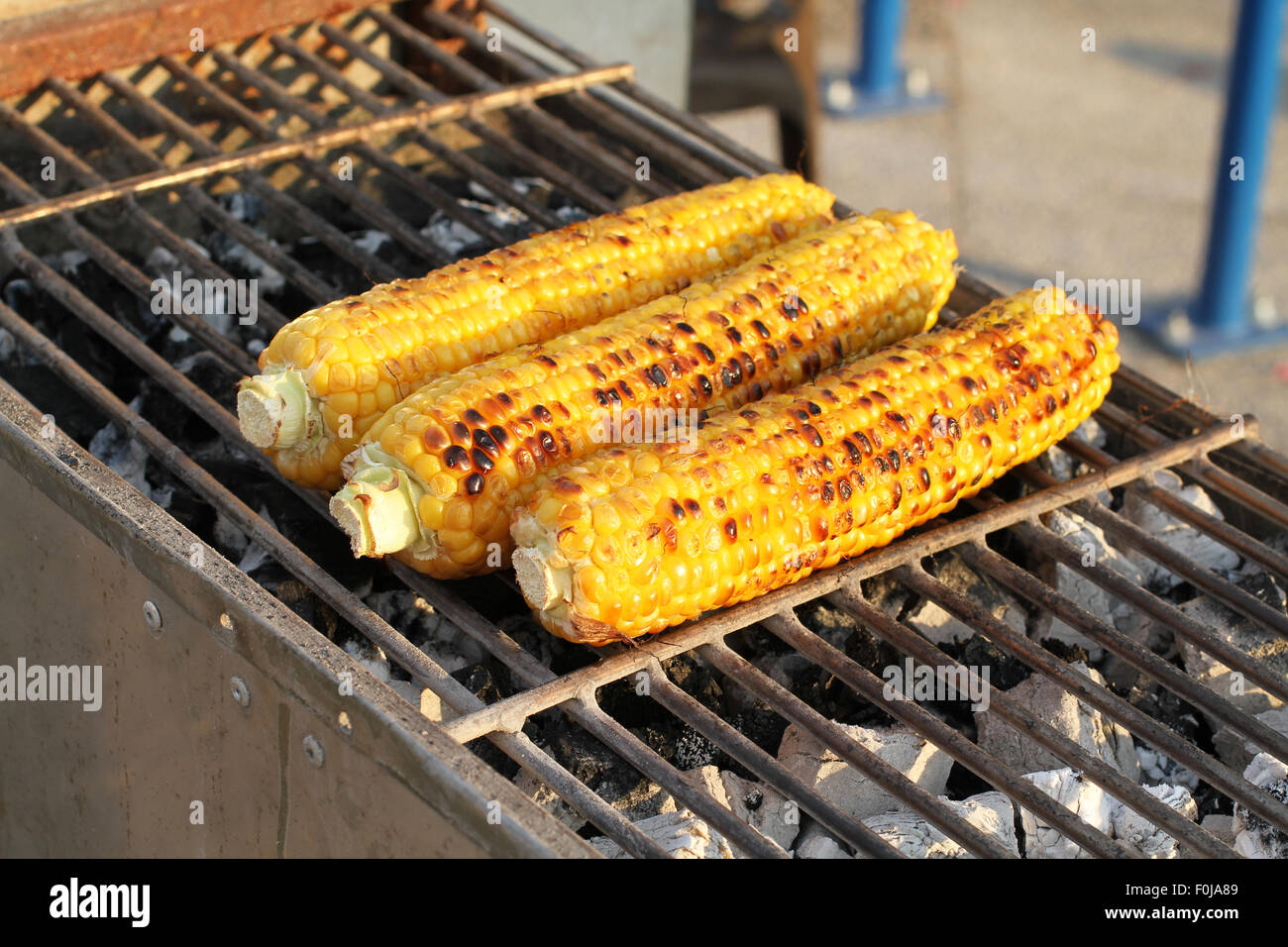 Roasted corn-cobs on brazier grid at the street. Closeup Stock Photo ...
