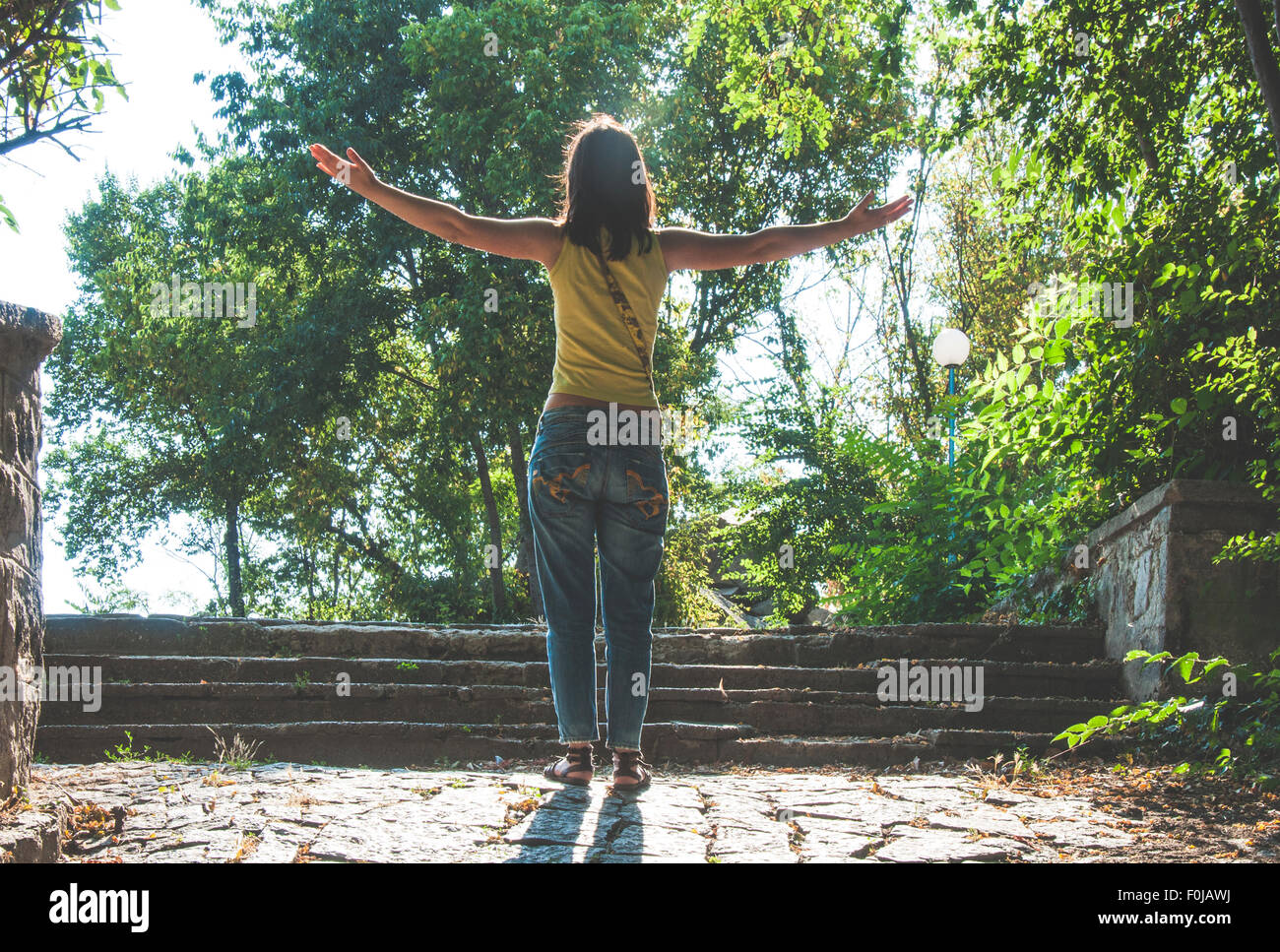Woman with arms outstretched against sun in the park Stock Photo - Alamy