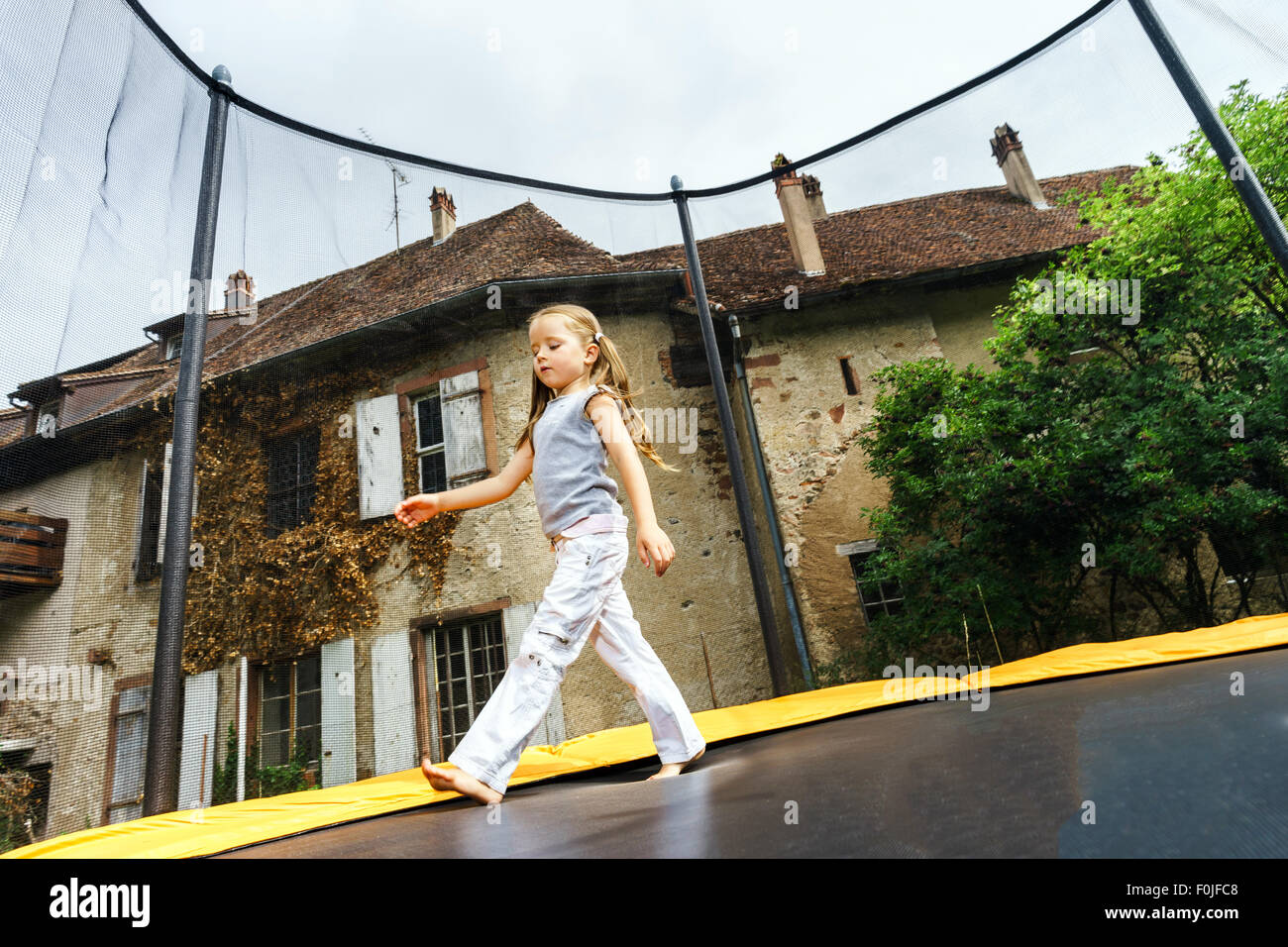 Cute preschooler girl jumping on trampoline, childhood concept Stock ...