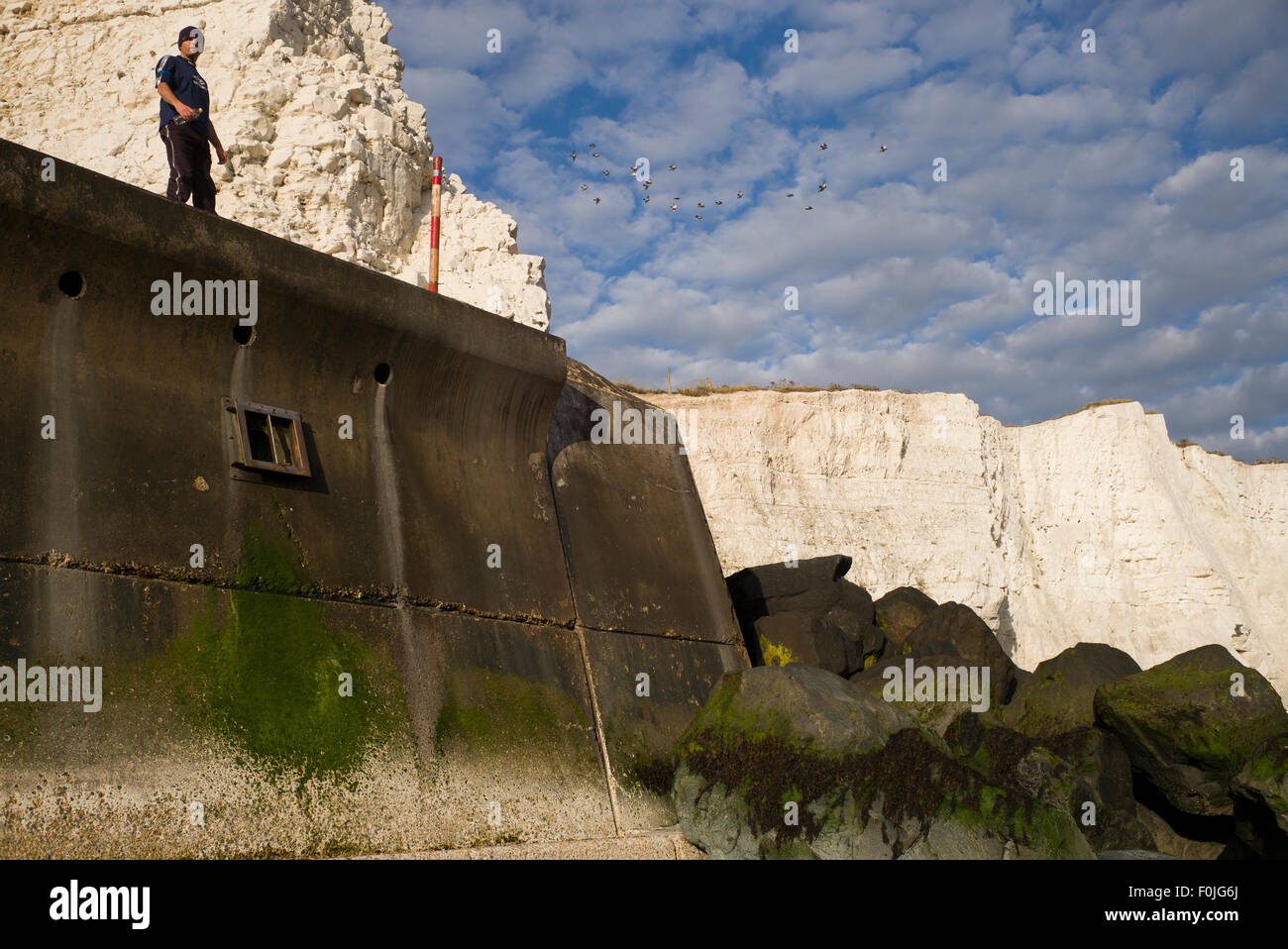 Man standing on sea wall, Saltdean, Sussex, low angle, cliffs in ...