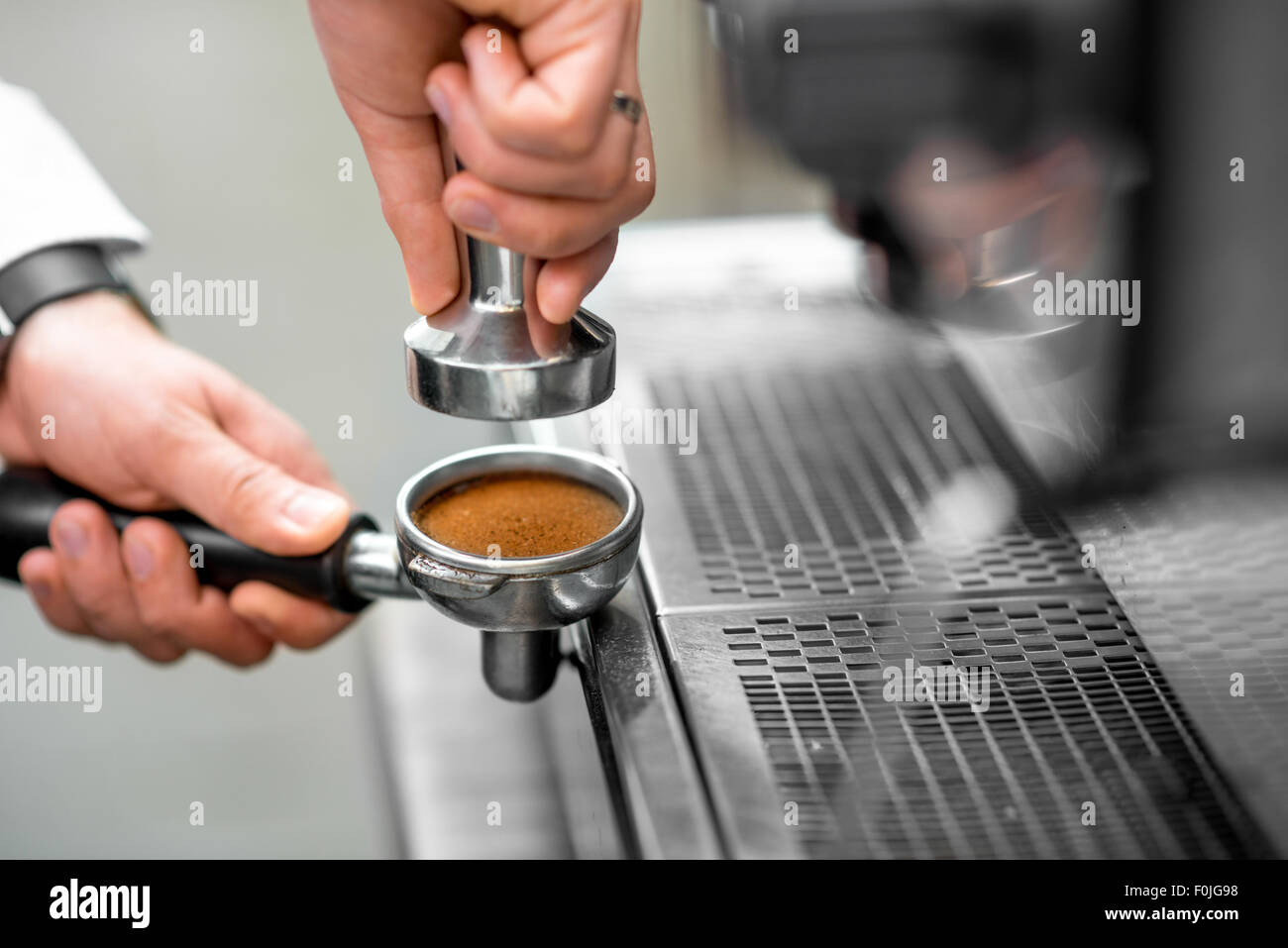Pressing coffee in the machine holder Stock Photo - Alamy