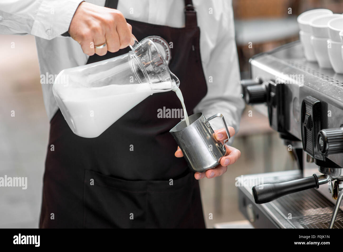 Barista pouring milk to the metal pitcher Stock Photo - Alamy