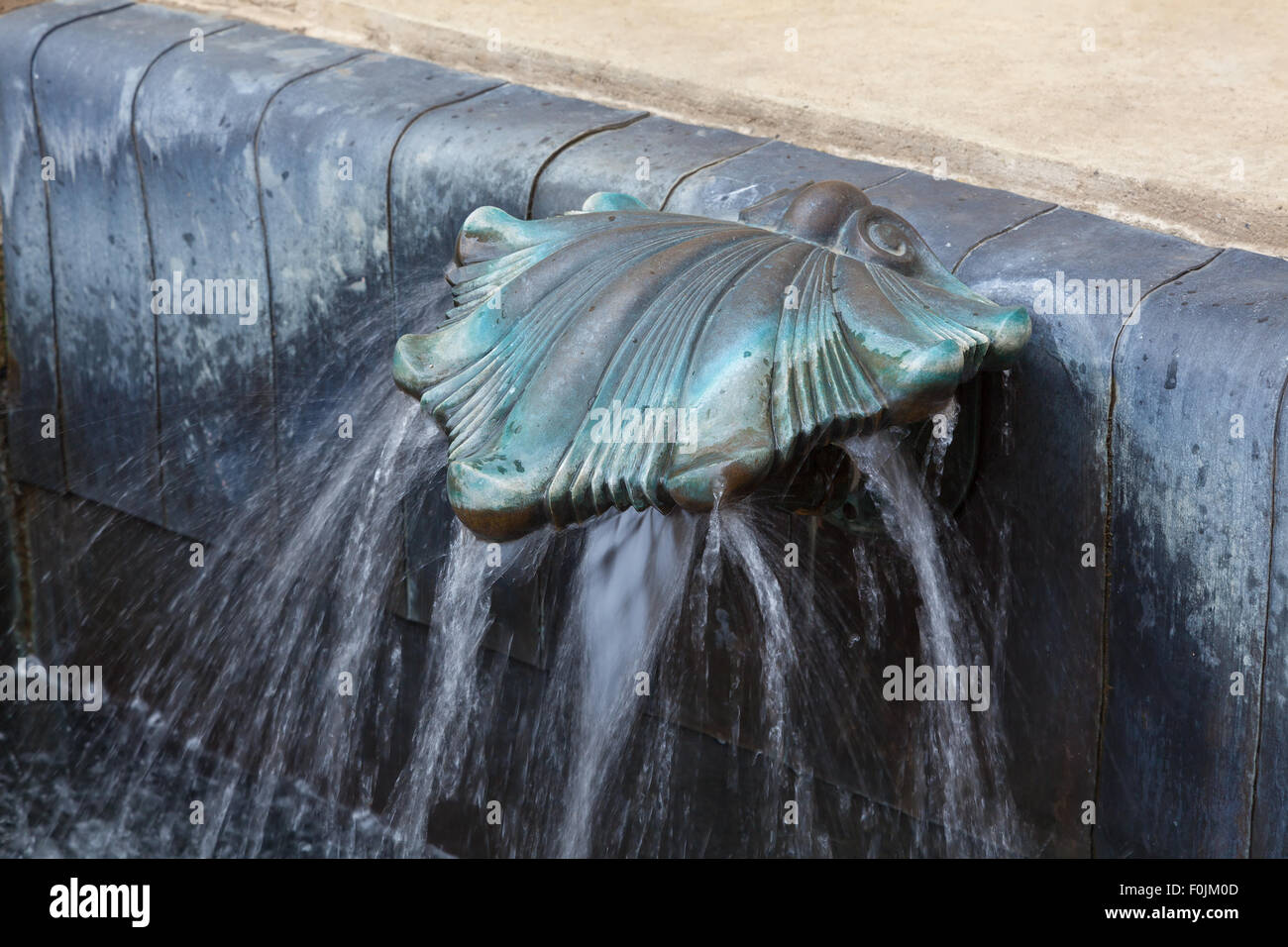 Bronze water faucet with spray of water gushing out Stock Photo - Alamy