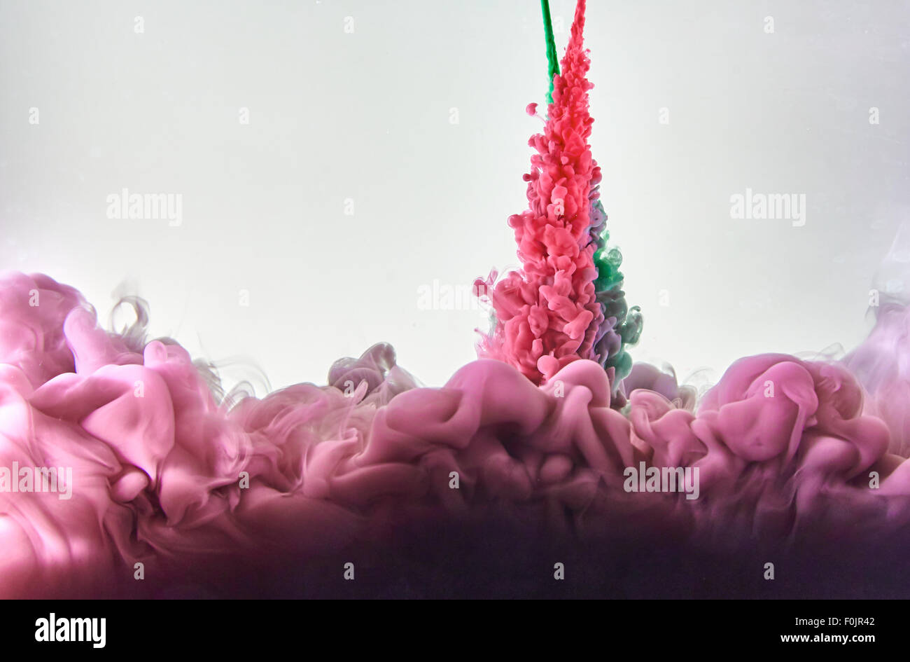 Red and green ink making clouds in water Stock Photo - Alamy