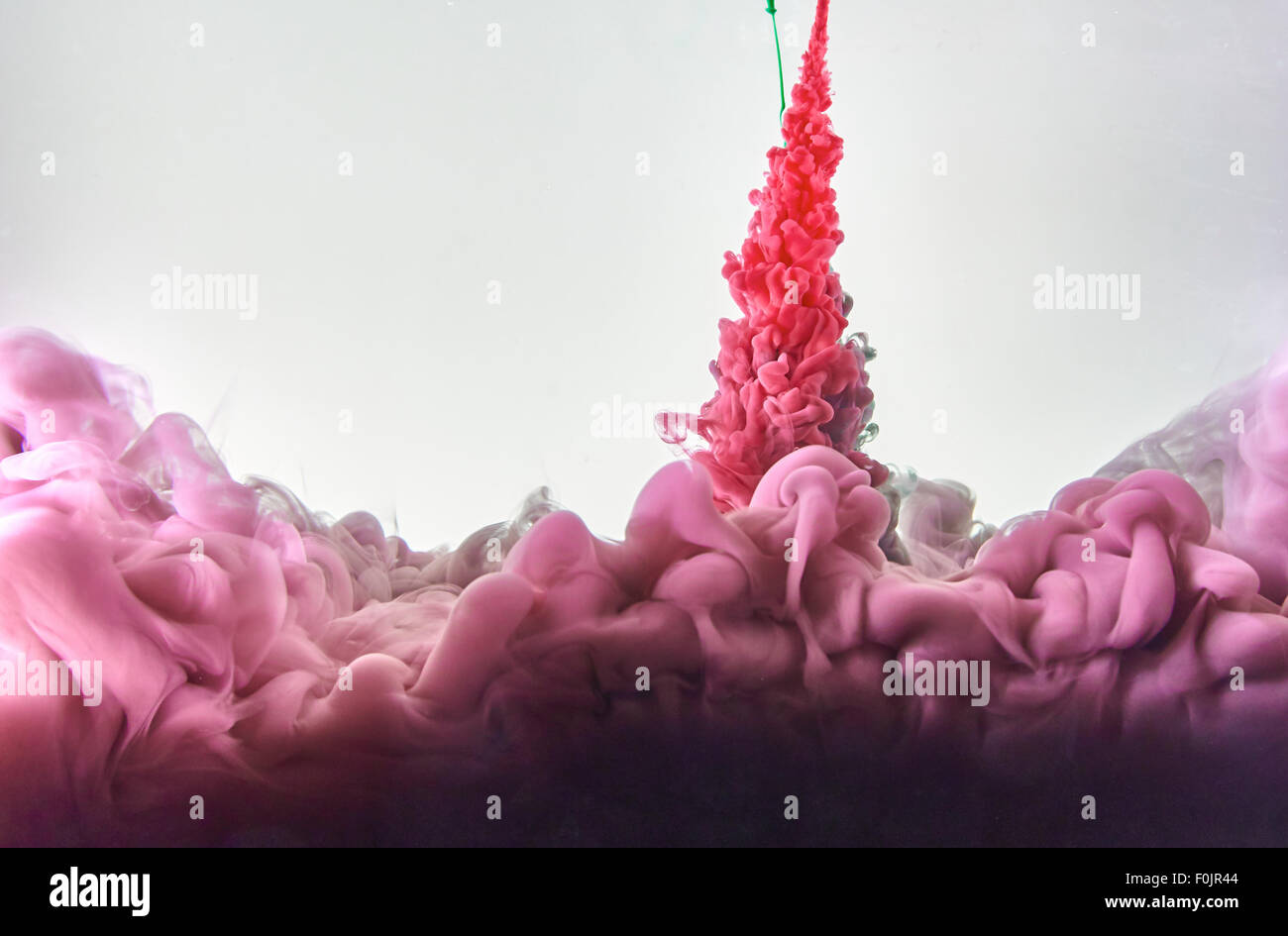 Red and green ink making clouds in water Stock Photo - Alamy