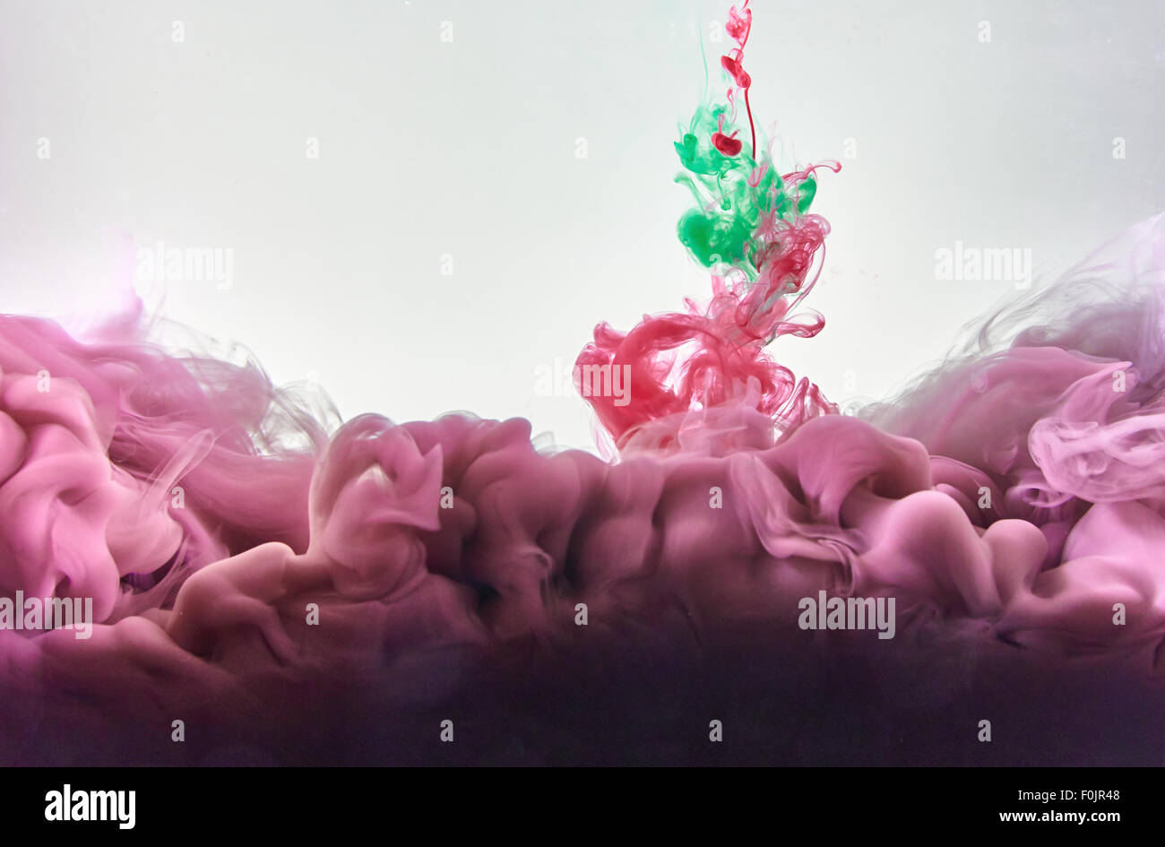 Red and green ink making clouds in water Stock Photo - Alamy