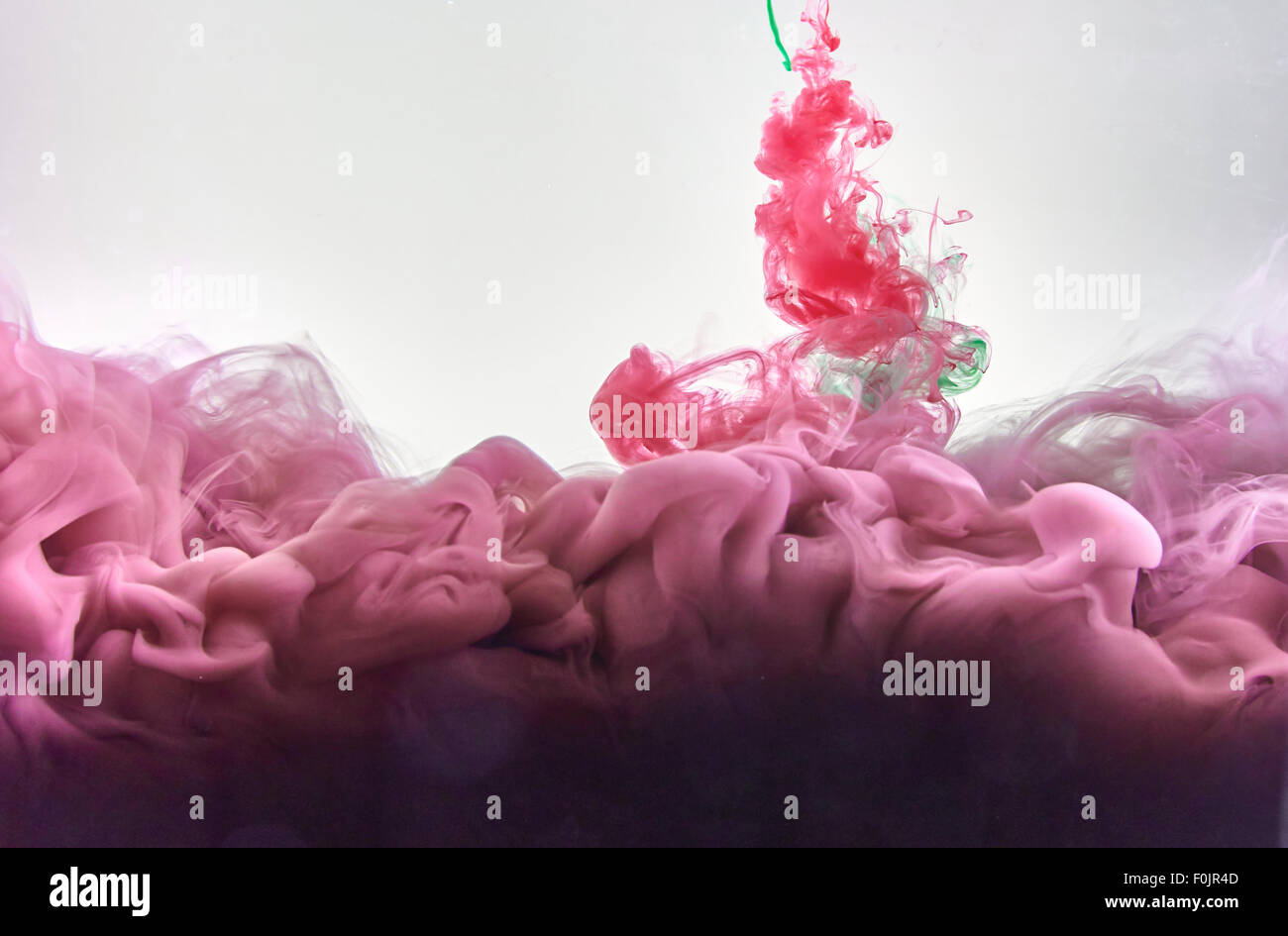 Red and green ink making clouds in water Stock Photo - Alamy