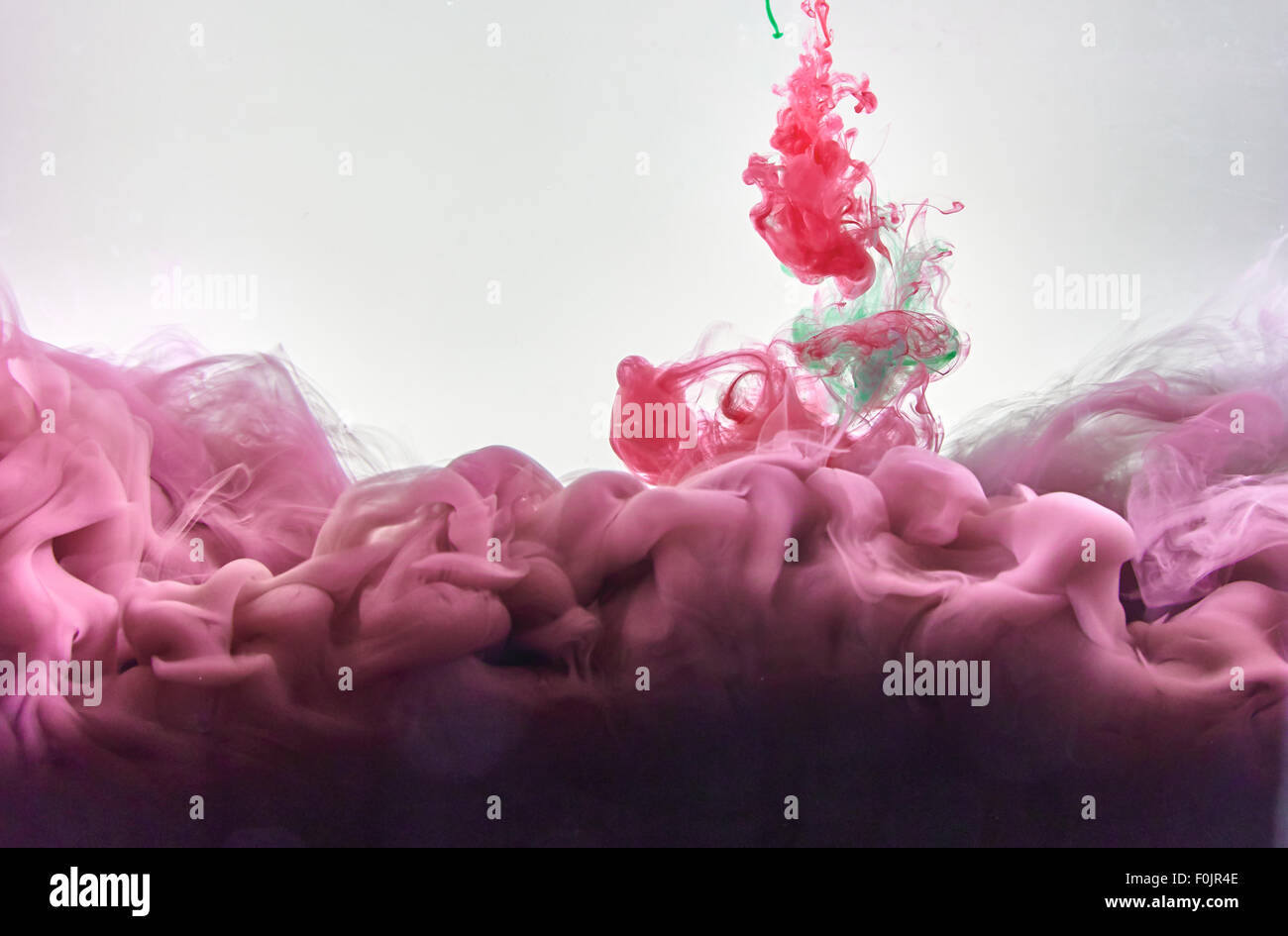 Red and green ink making clouds in water Stock Photo - Alamy