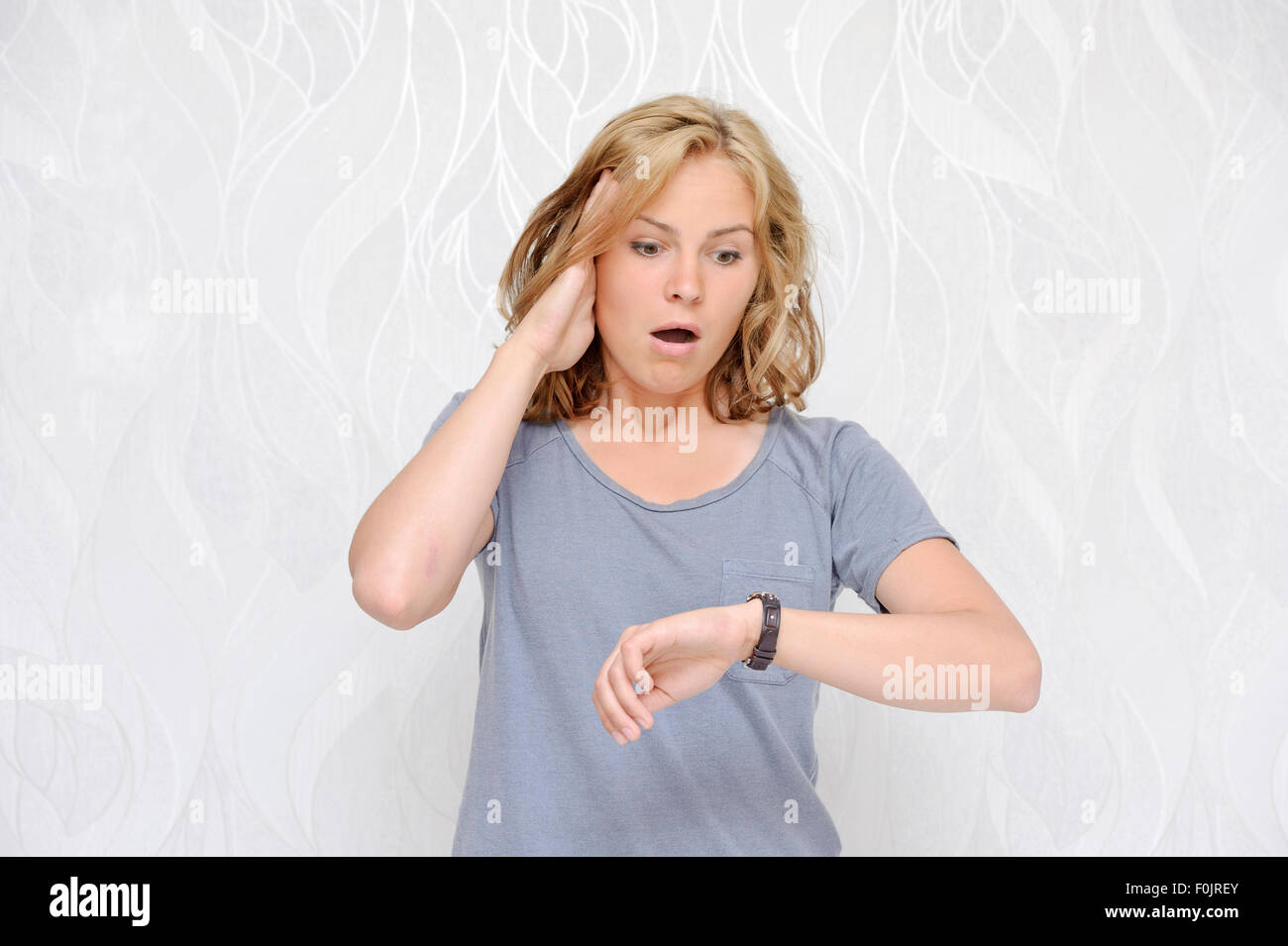 Young woman looking at her watch being late Stock Photo - Alamy